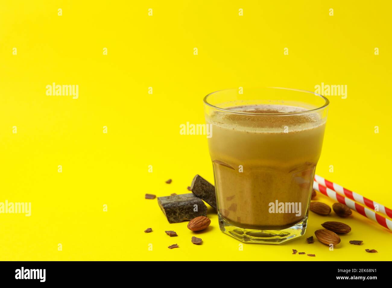 Chocolate milkshake, almond, chocolate and straws on yellow background ...