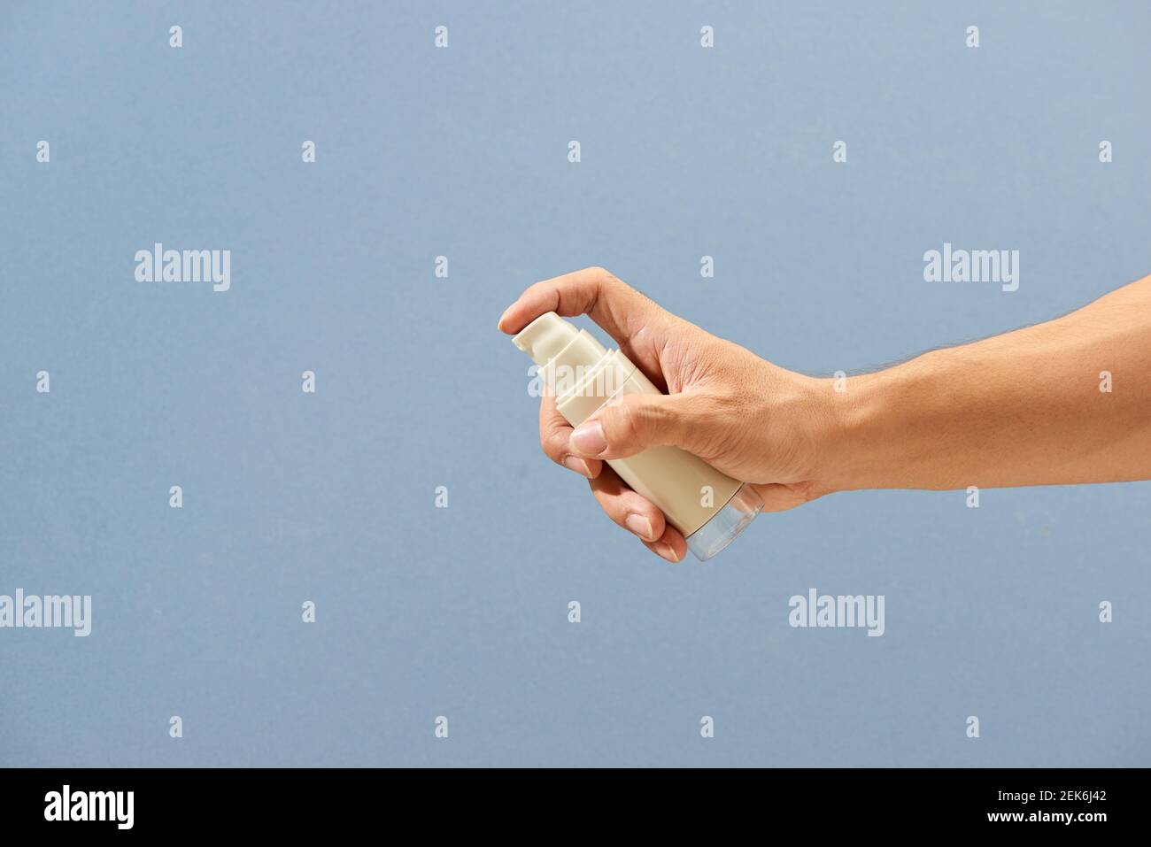 Hand holding spray bottle isolated on light blue background with ...