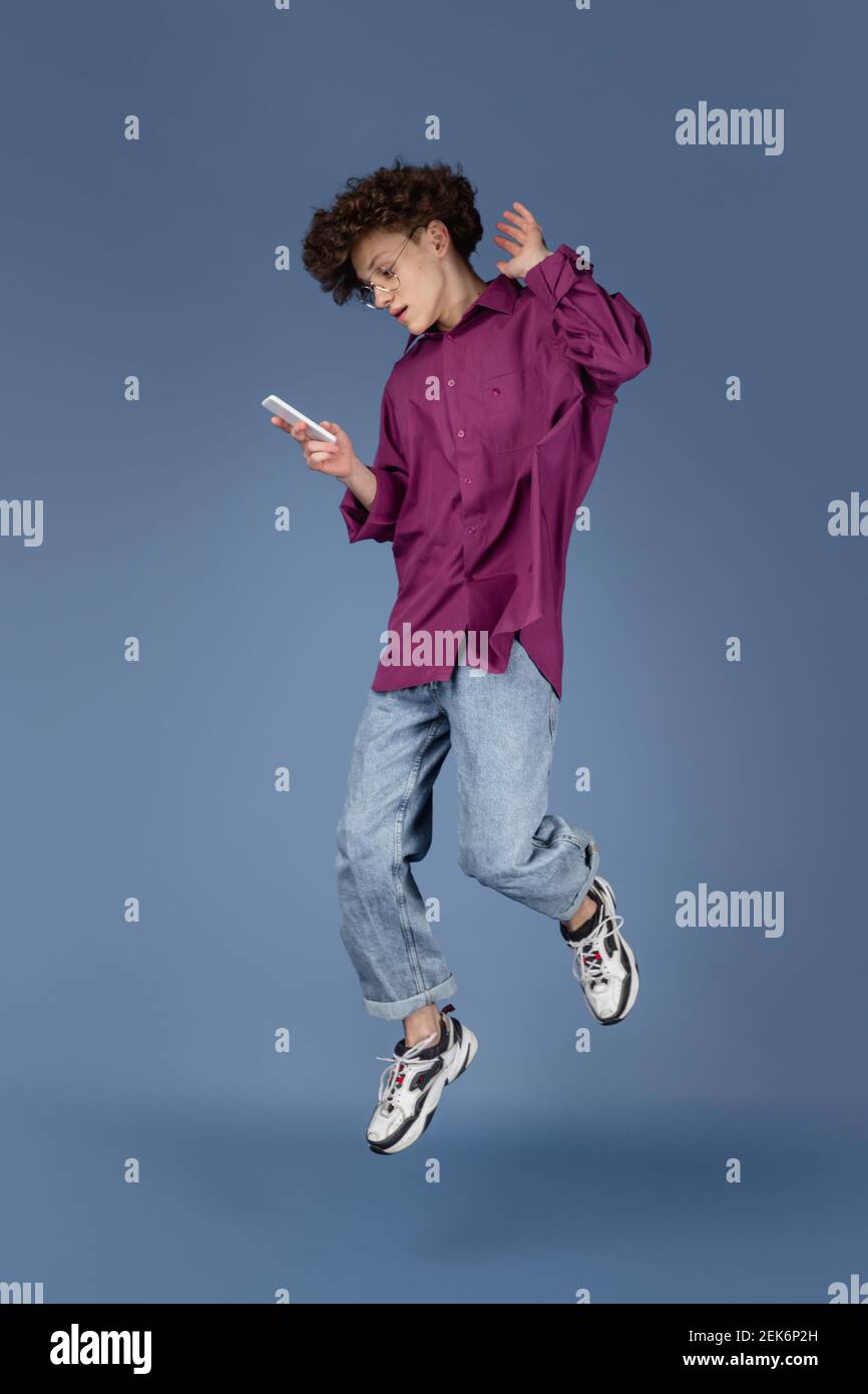 Jumping high. Caucasian young handsome man's portrait on blue studio ...