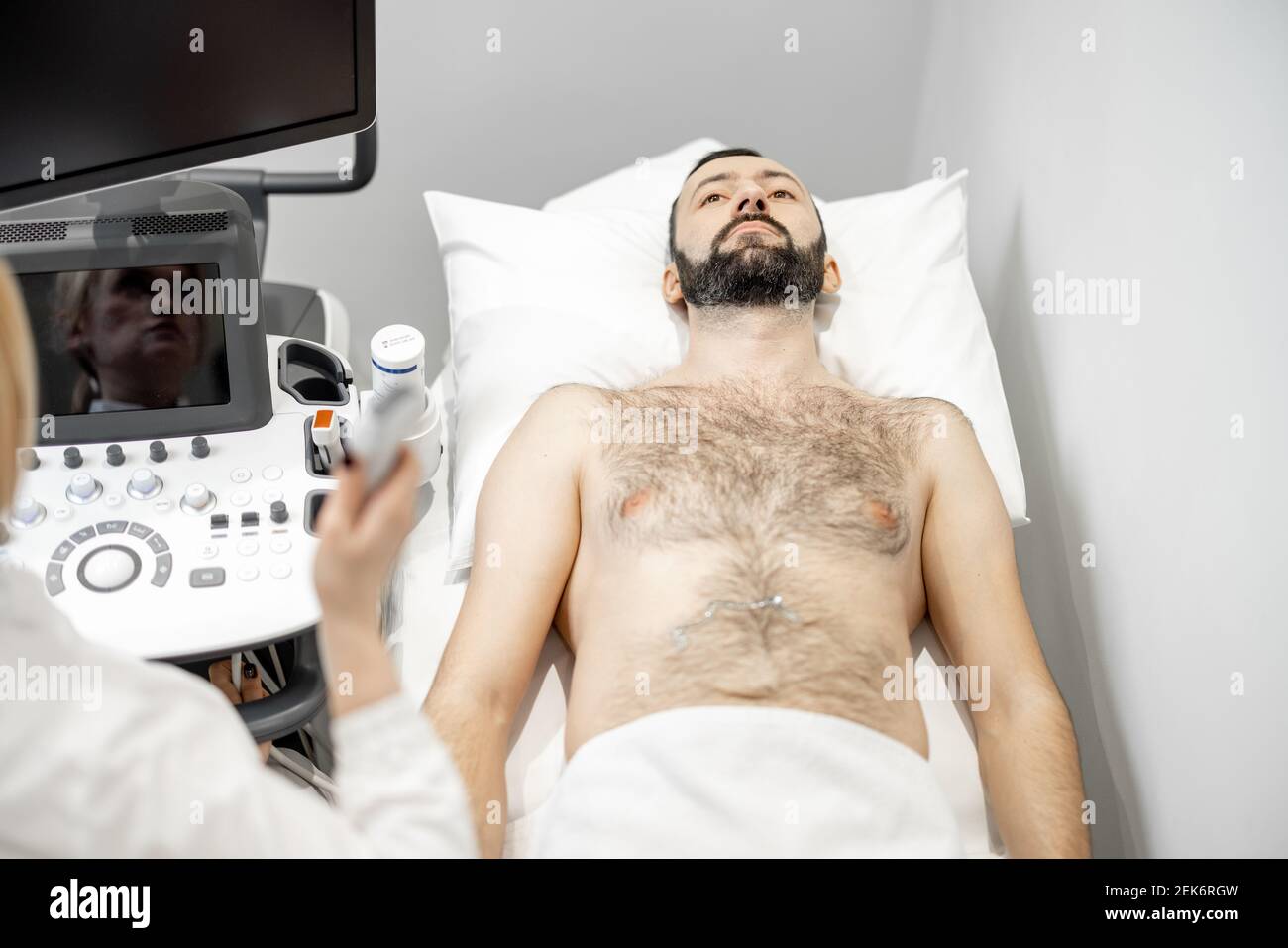 Doctor examining liver of male patient with ultrasound scan in clinic ...