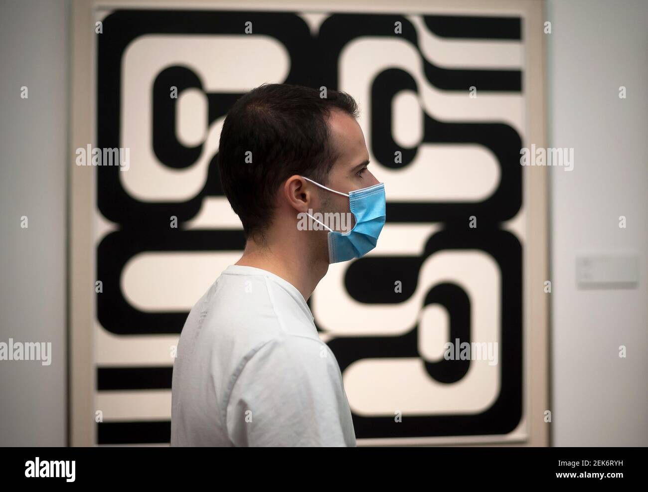 A visitor wearing a face mask is seen front a painting exhibition at ...