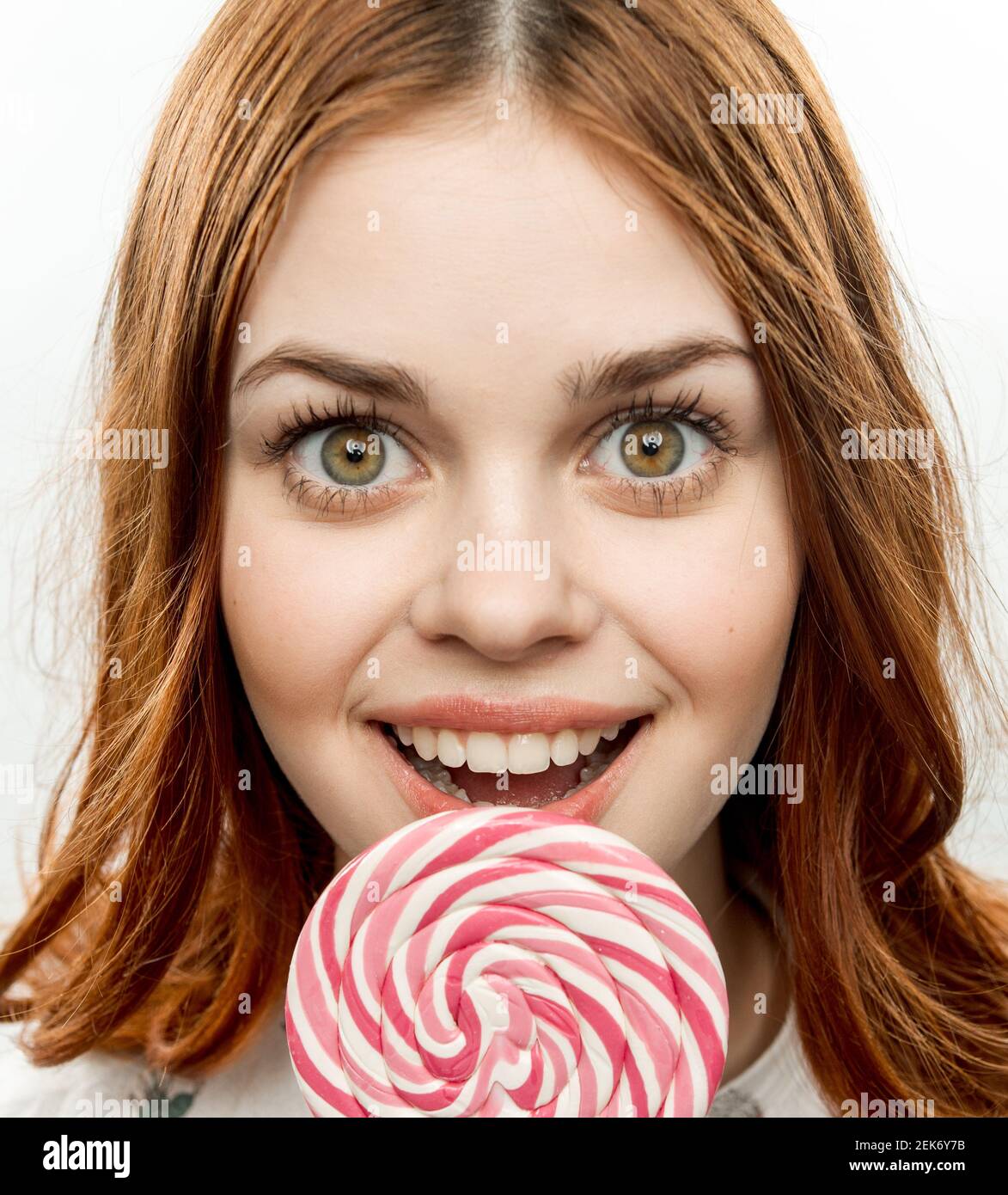 attractive red-haired woman licking lollipop face fun Stock Photo - Alamy