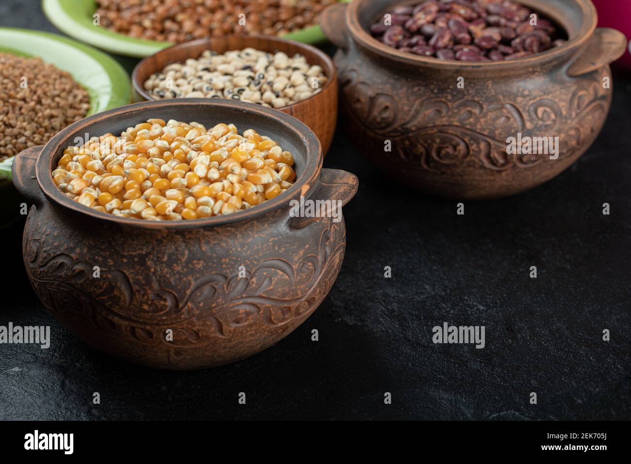 Different kinds of bean seeds, lentil, peas in dishes on a dark ...