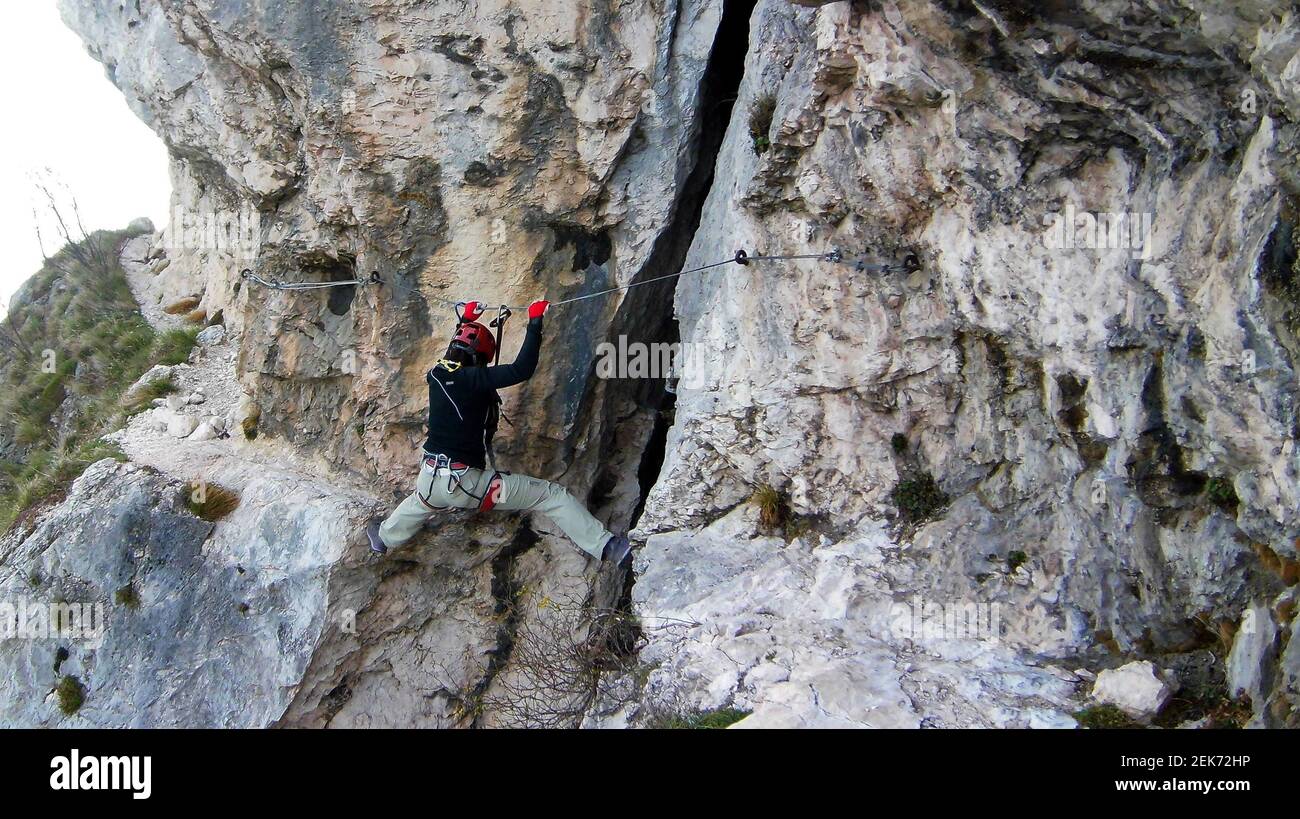 Climber with red climbing helmet doing the balancing act on a dangerous ...