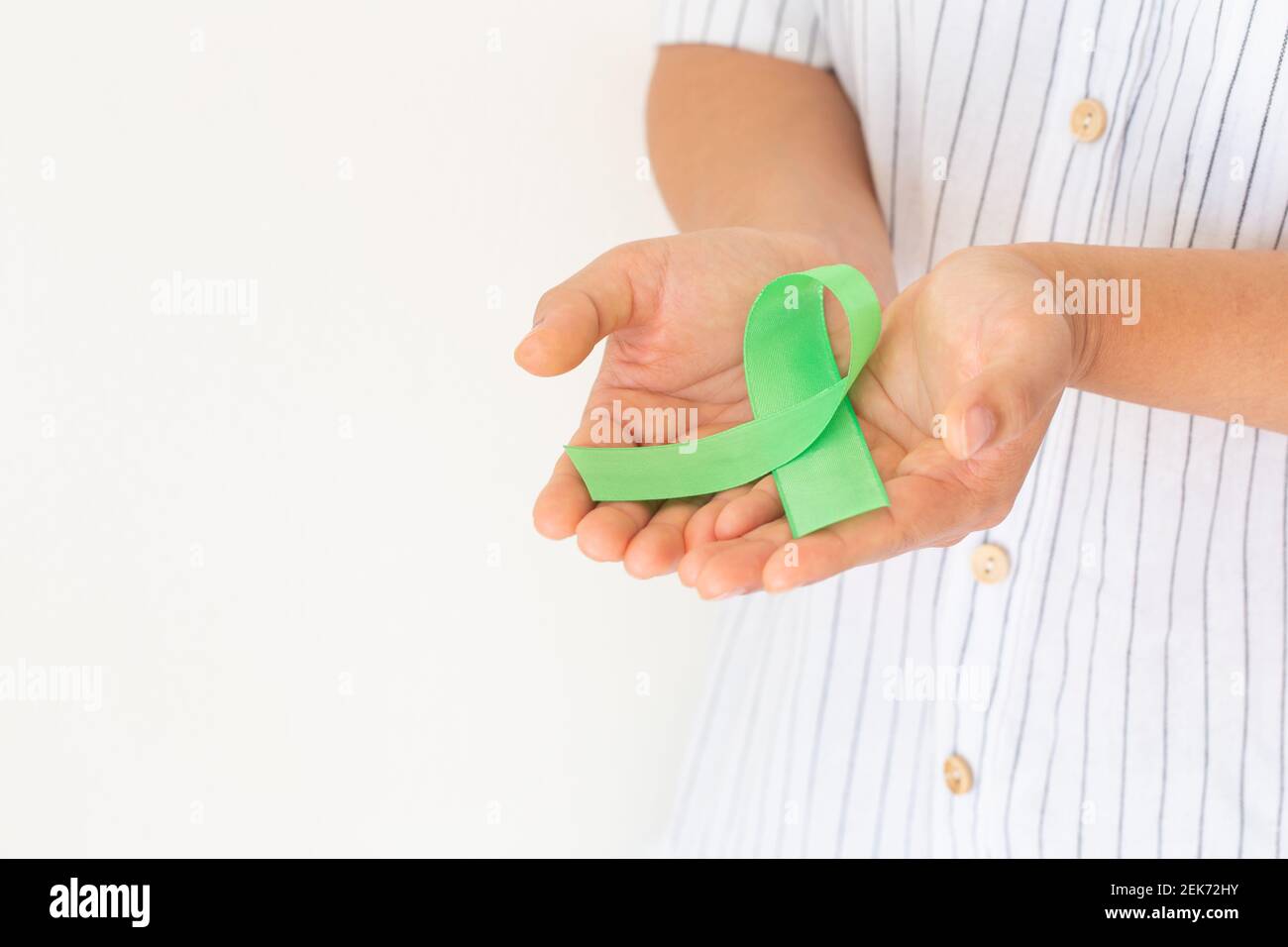 Hands holding emerald green or jade green ribbon on white background ...