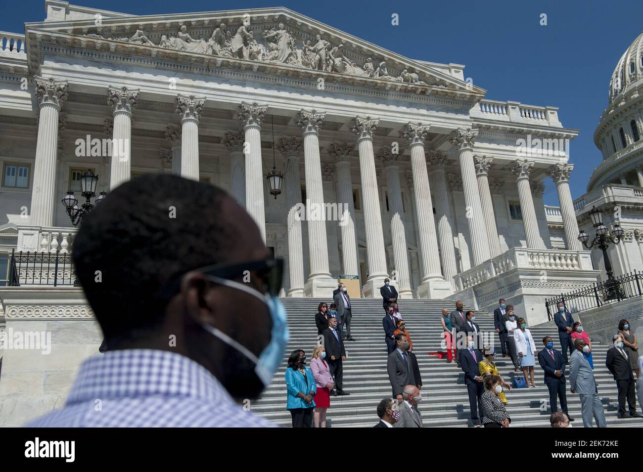 Members of Congress on the House steps of the US Capitol stand at a ...