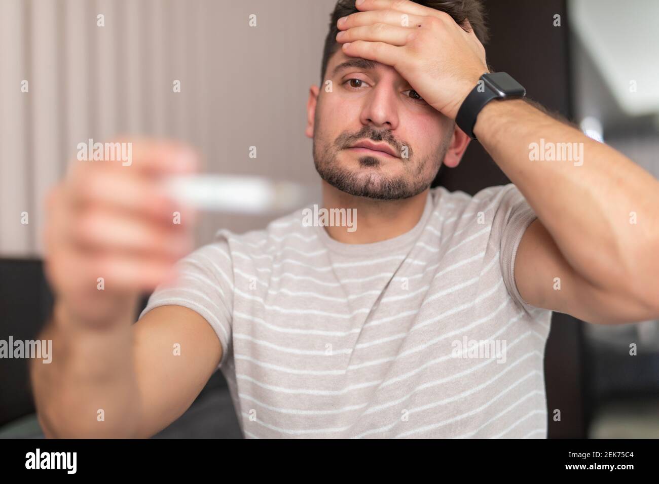 Sick man in bed measuring temperature feeling fever Stock Photo - Alamy