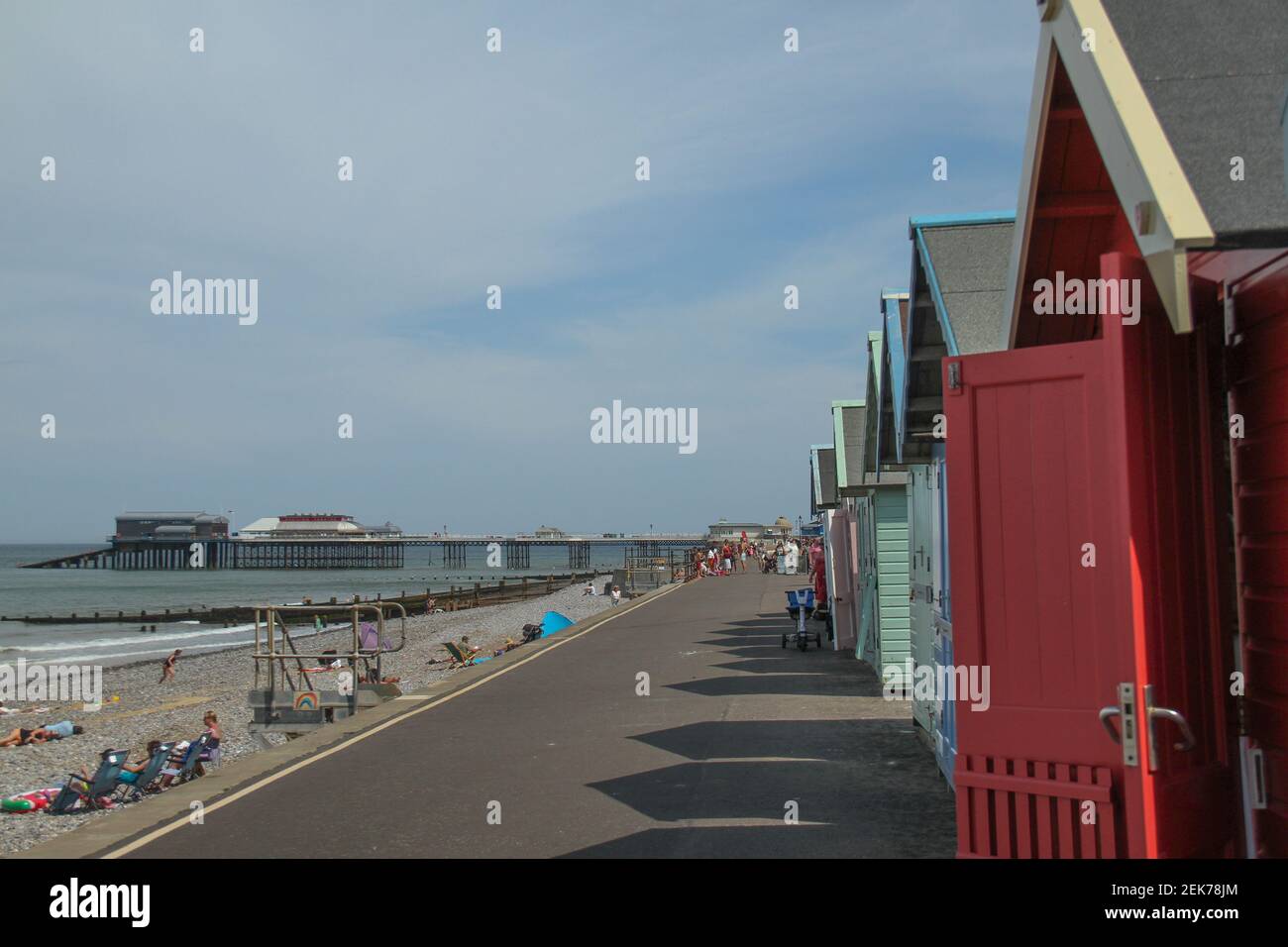 Cromer pier and the sea front seen from the beach huts. People enjoy ...