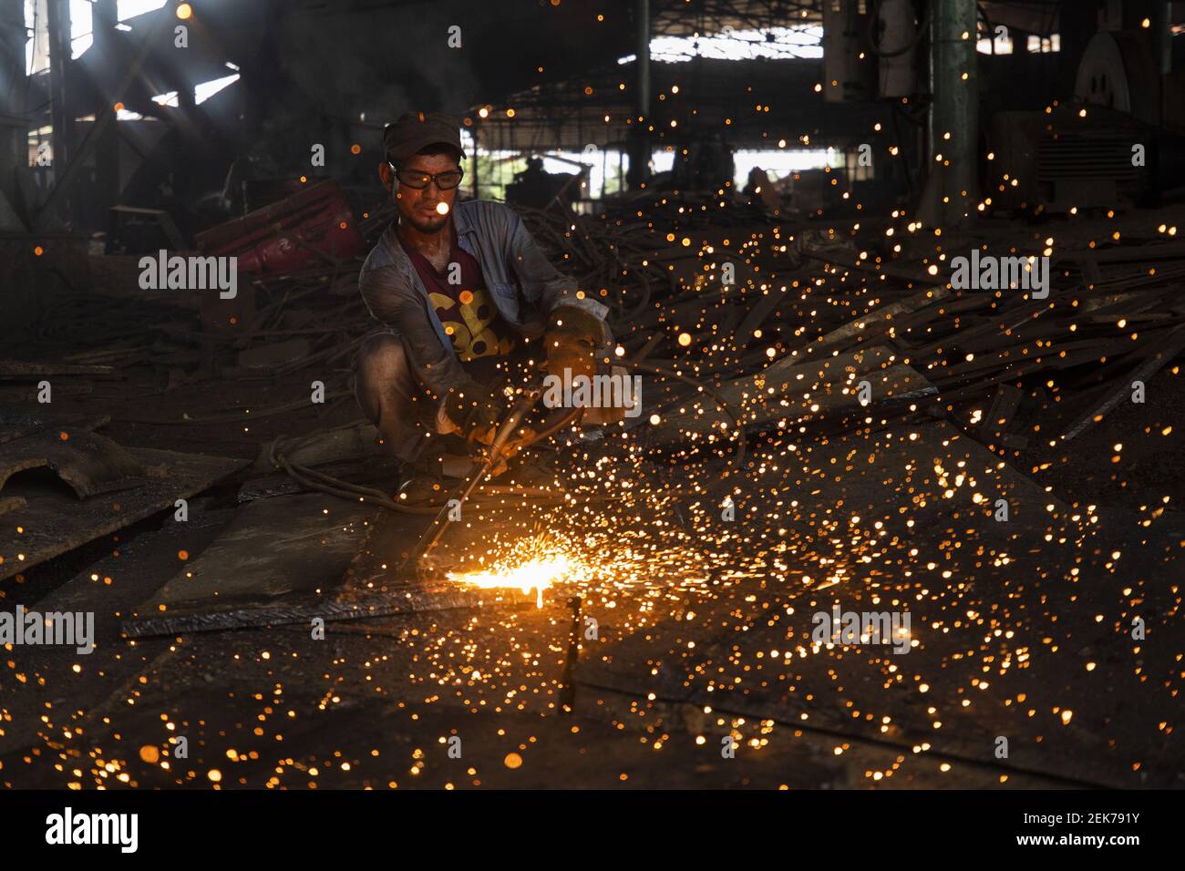 A still re-rolling worker cuts a metal plate with gas flame in Narayanganj, on the outskirts of ...