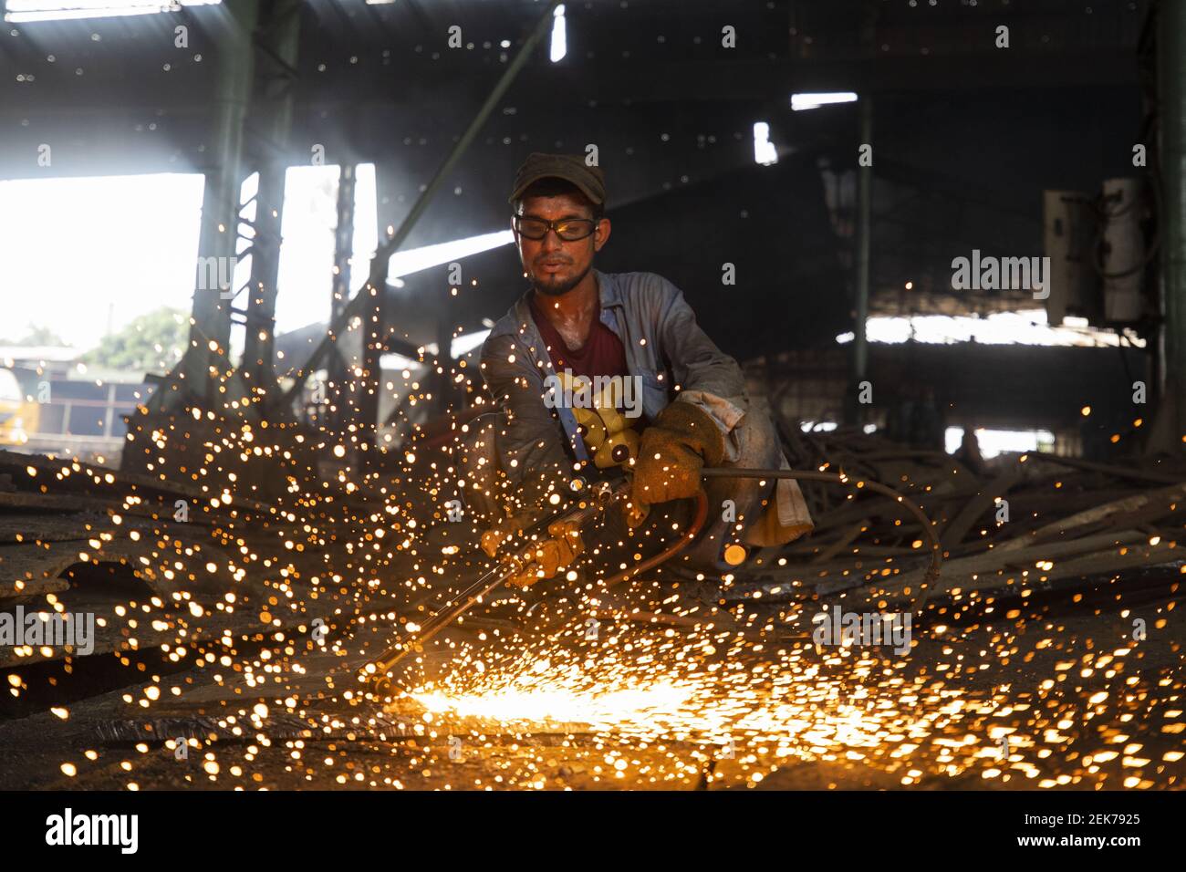 A still re-rolling worker cuts a metal plate with gas flame in Narayanganj, on the outskirts of ...