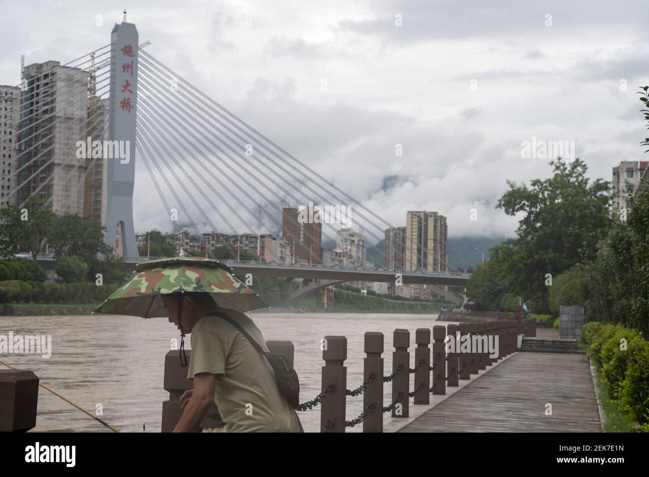 ENSHI, CHINA - JUNE 28, 2020 - An old man is fishing near the river ...
