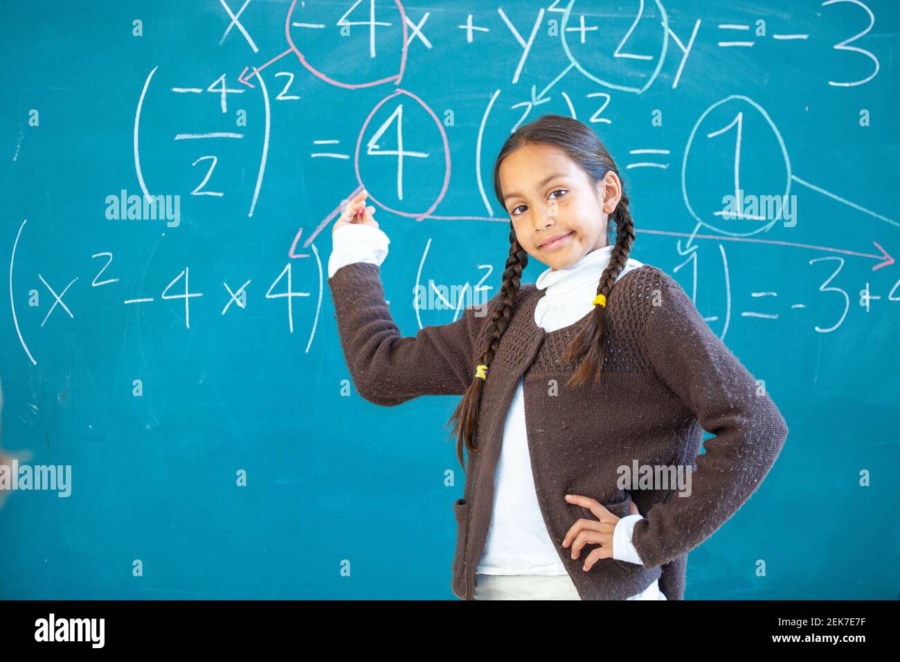 Smart young girl solving equations in an elementary school classroom ...