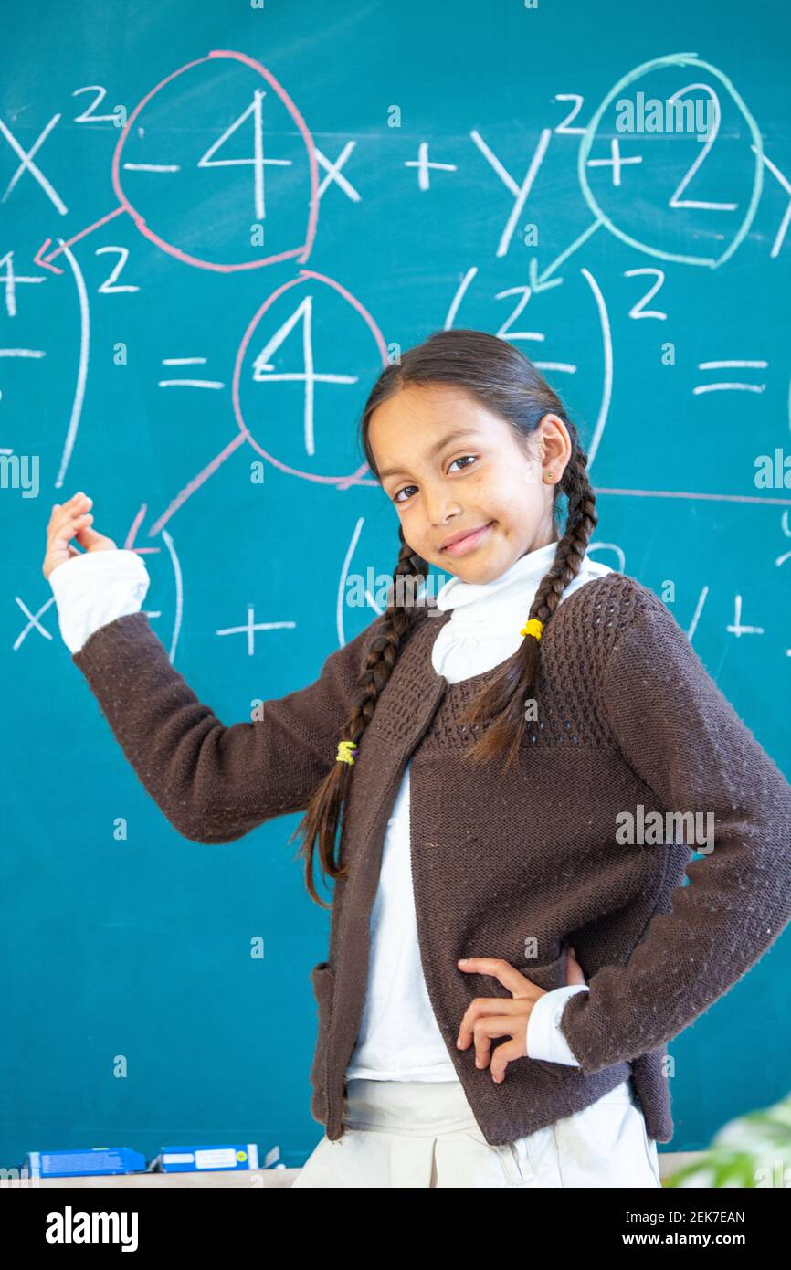 Smart young girl solving equations in an elementary school classroom ...