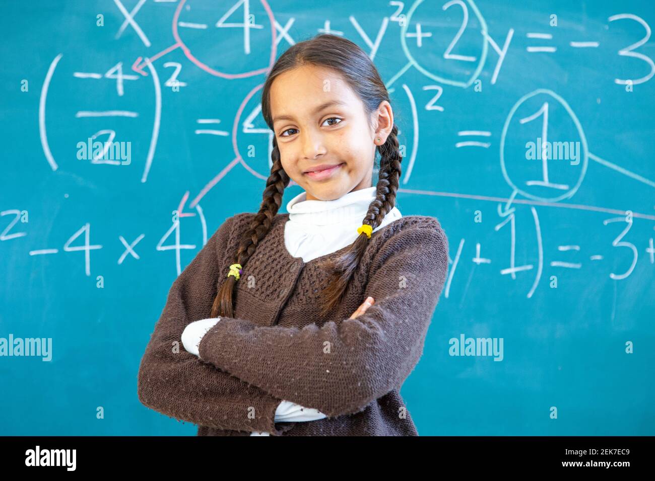 Smart young girl solving equations in an elementary school classroom ...