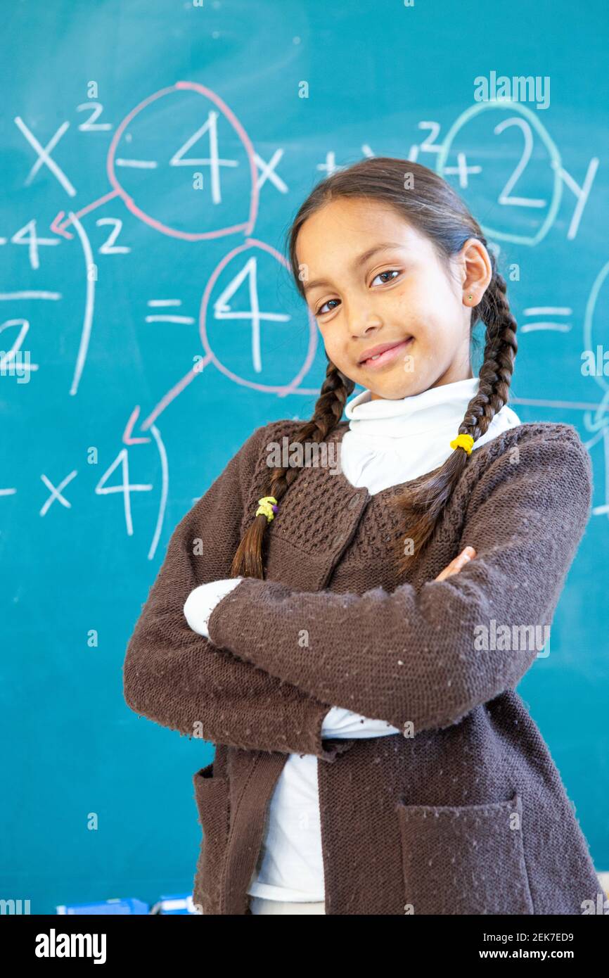 Smart young girl solving equations in an elementary school classroom ...