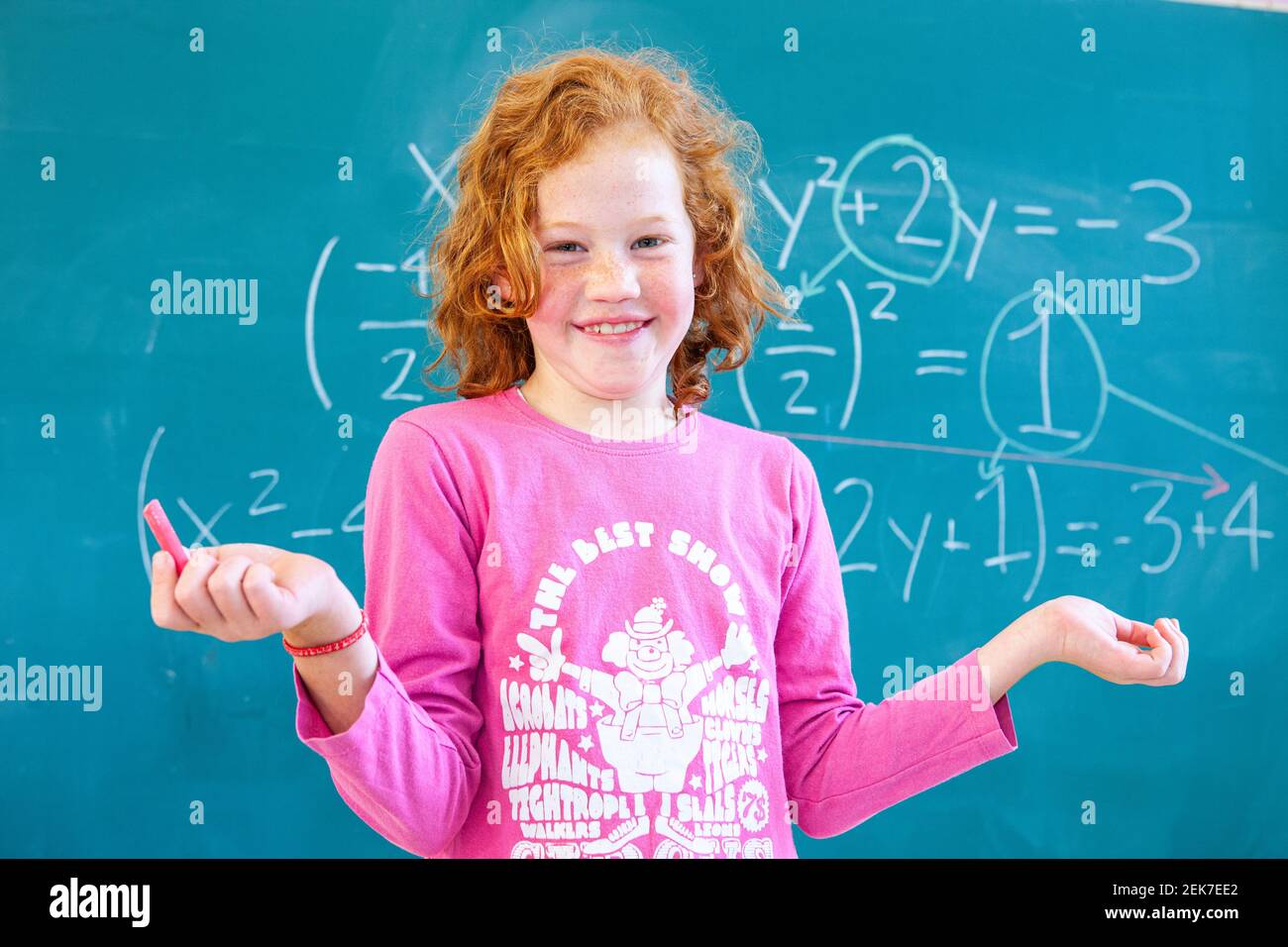 Smart young girl solving equations in an elementary school classroom ...