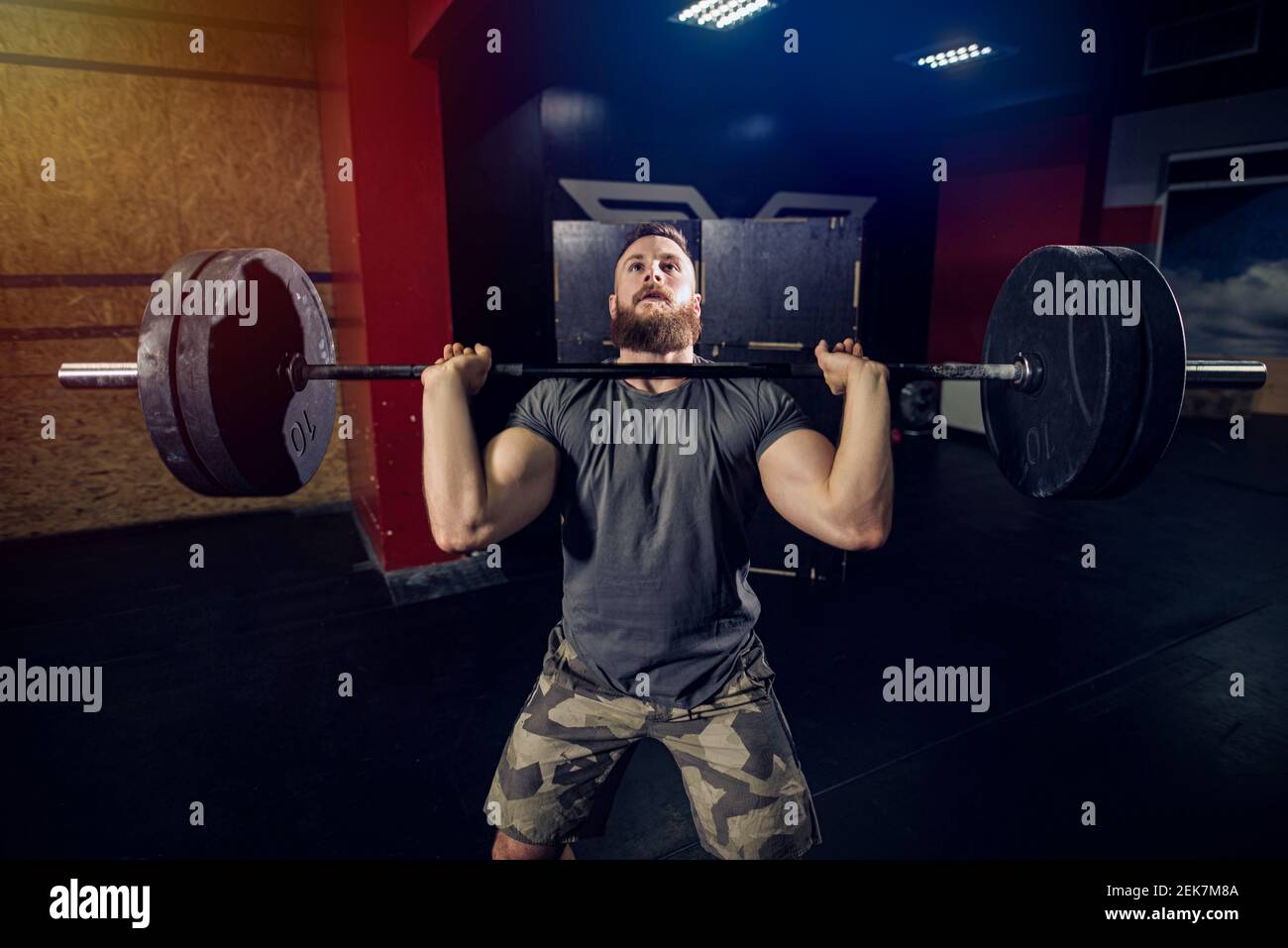 Bearded strong sporty man lifting heavy weight in dark room Stock Photo ...