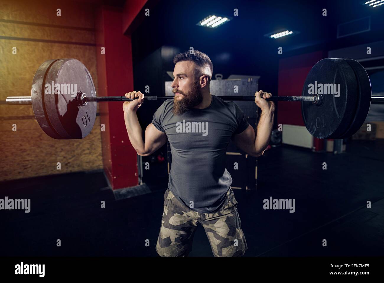 Bearded strong sporty man lifting heavy weight in dark room Stock Photo ...