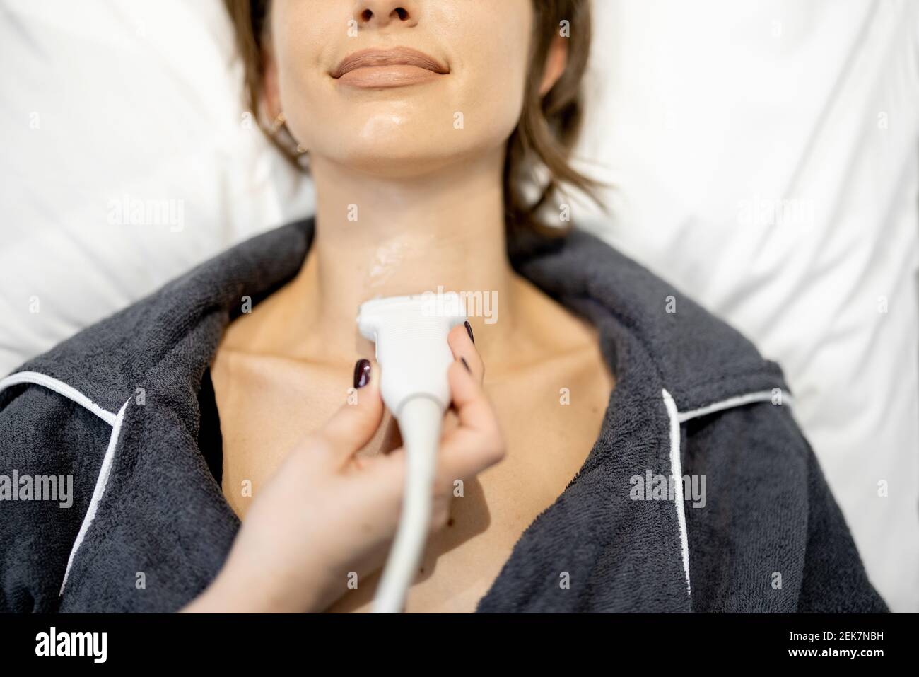 Doctor examining thyroid of female patient with ultrasound scan in ...