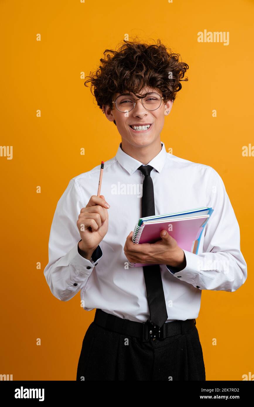 Cheerful young man student taking notes while standing isolated over ...