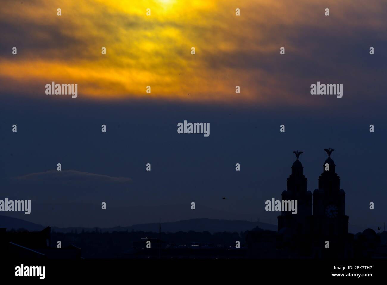 The sun sets behind the Liver building, in Liverpool. Picture date ...