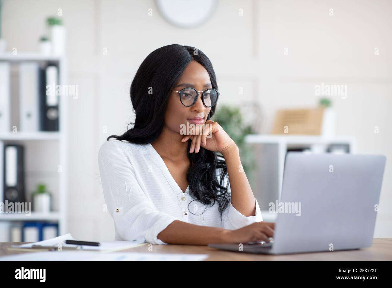 Positive female manager using laptop computer at workplace, typing ...