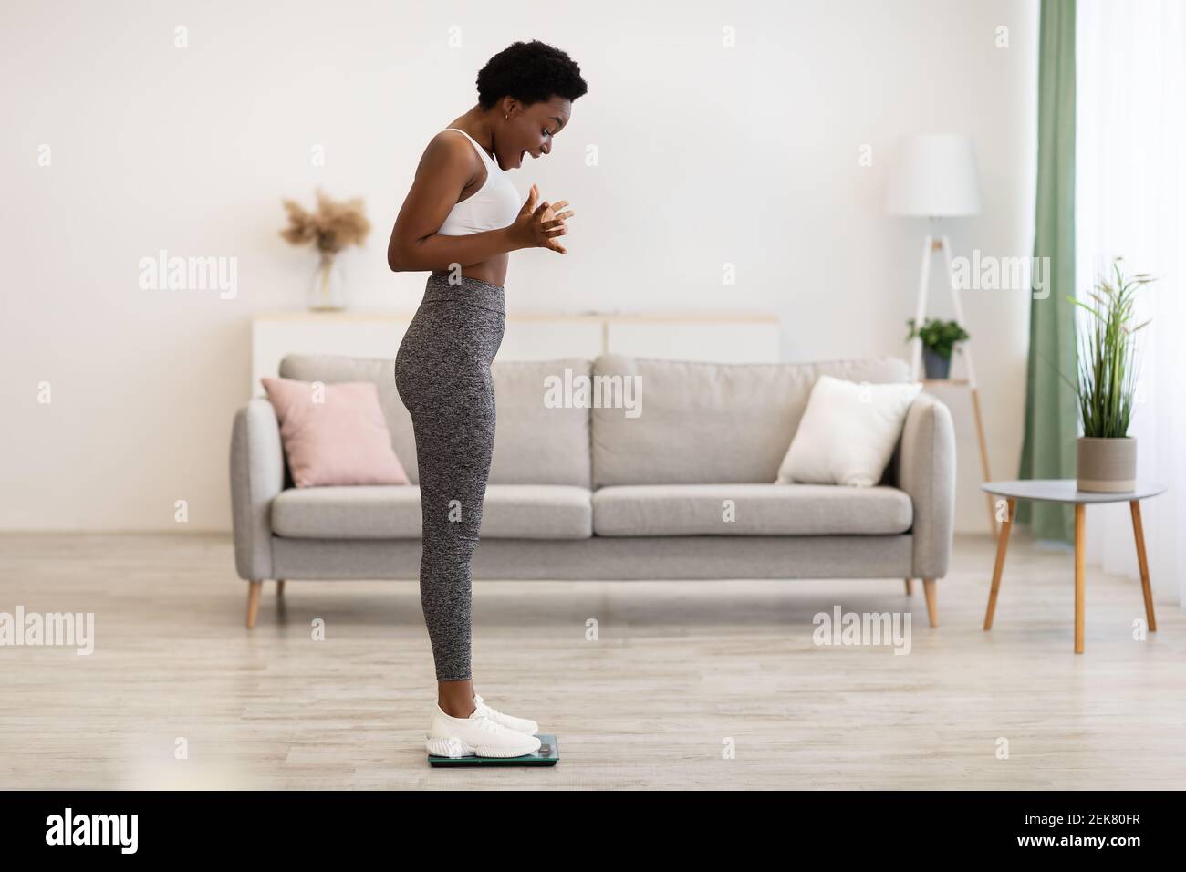 Joyful Black Lady Weighing Standing On Weight-Scales At Home Stock ...
