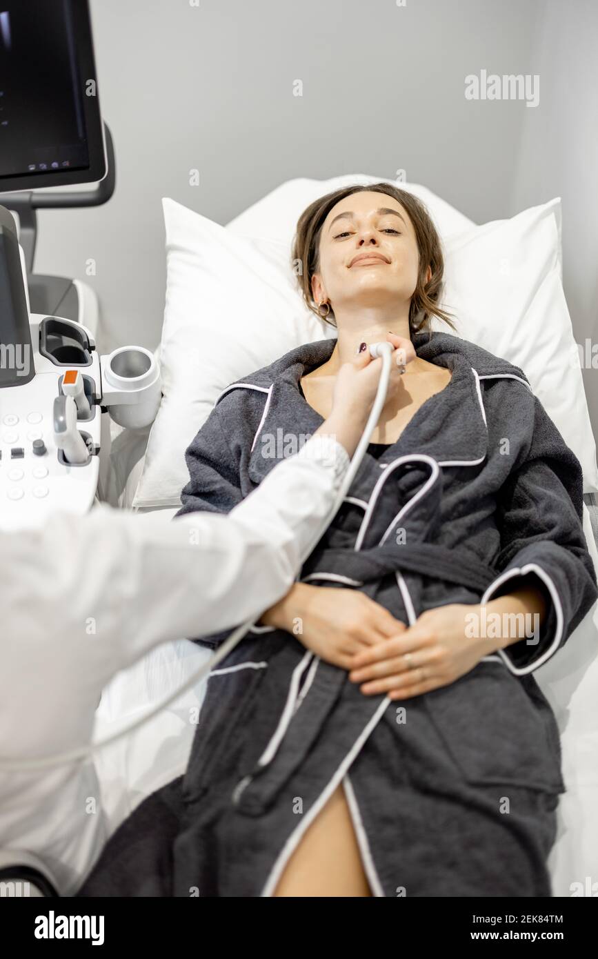 Doctor examining thyroid of female patient with ultrasound scan in ...