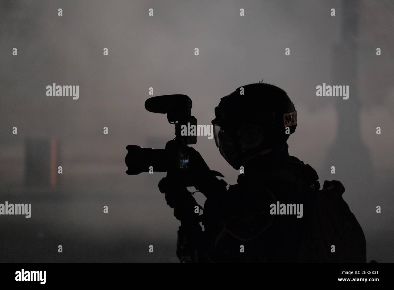 A member of the media films the scene as tear gas fills the air outside ...