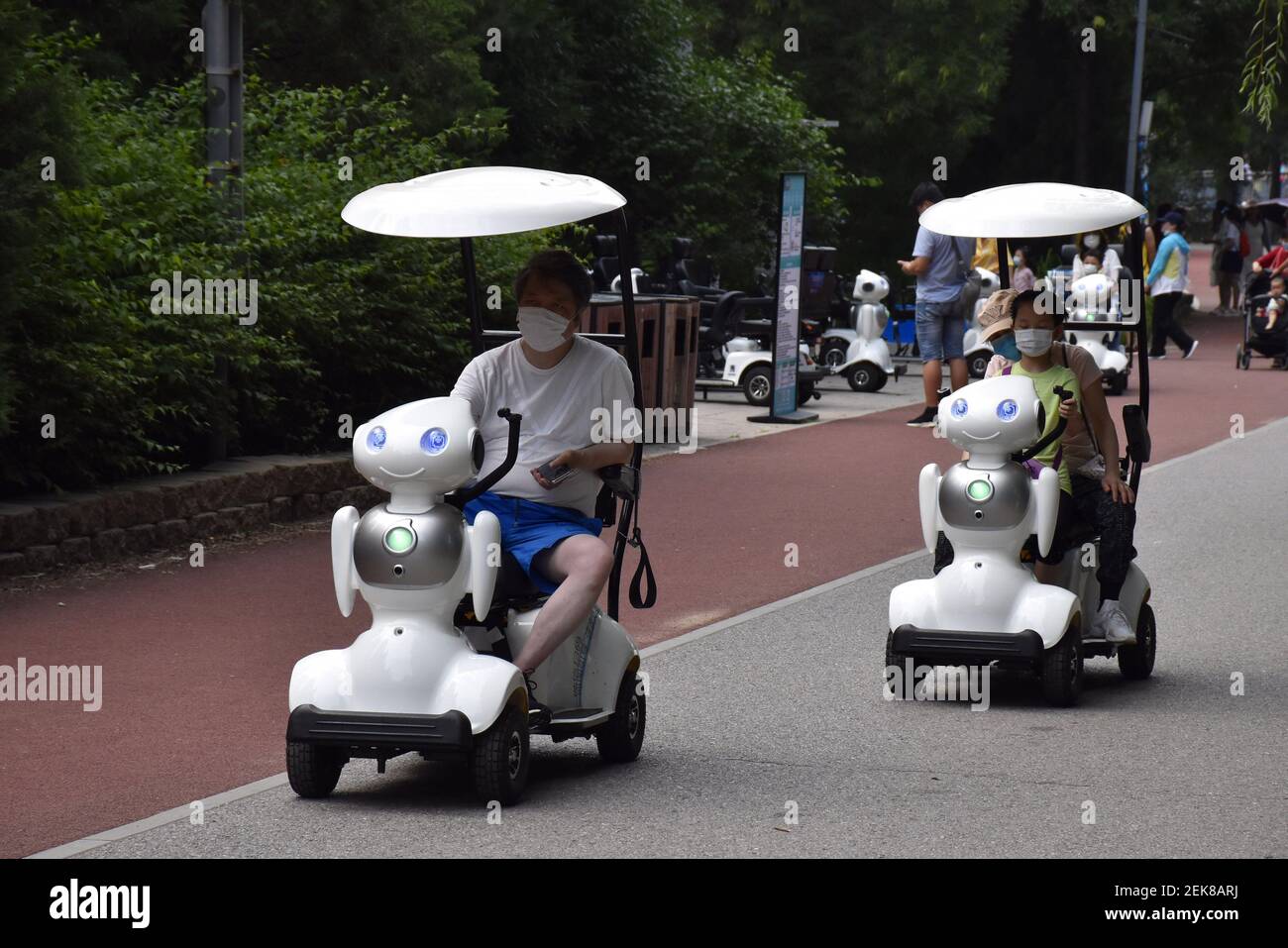 People ride on the robots designed for tour guide at the Olympic Forest ...
