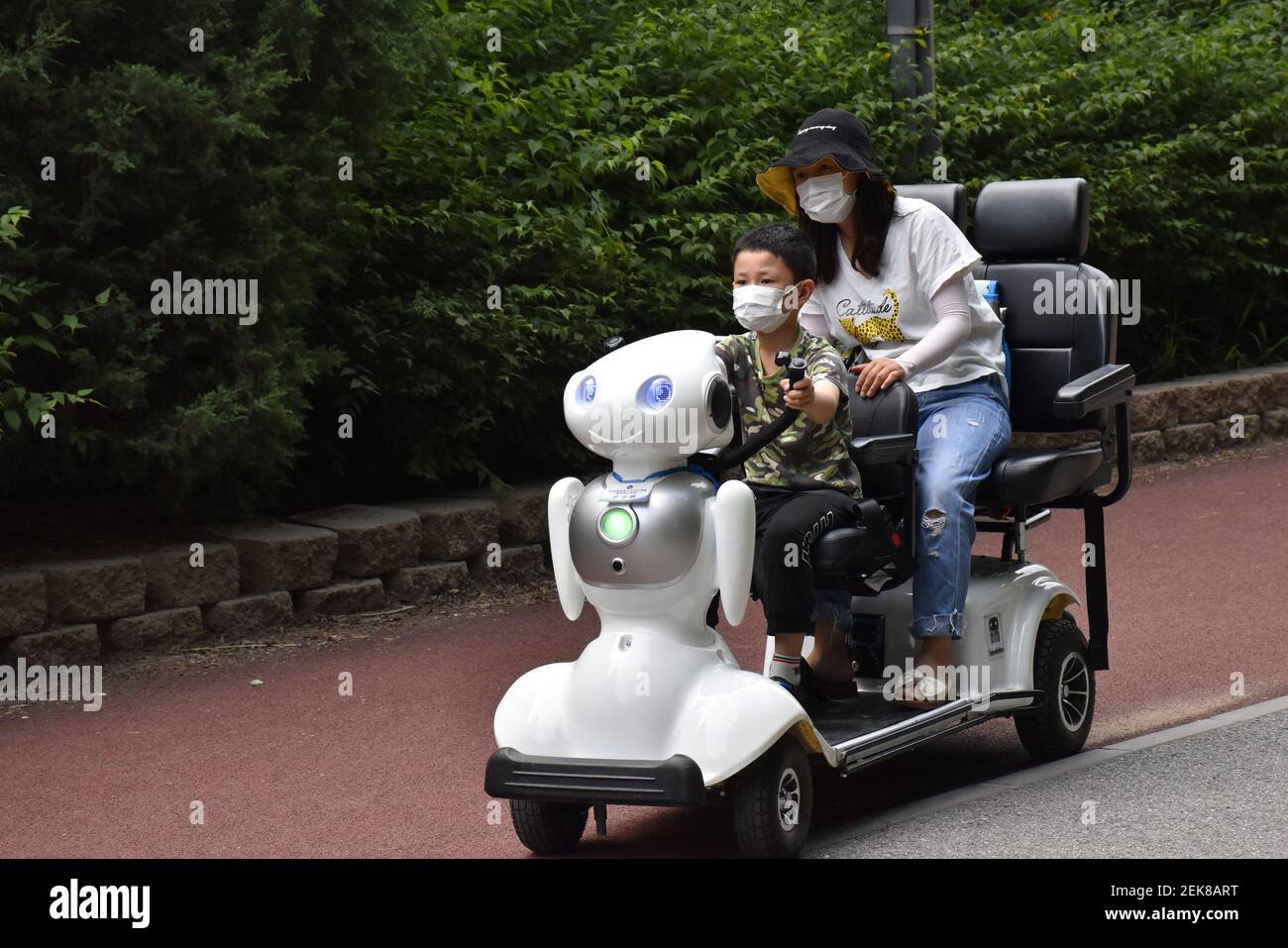 People ride on the robots designed for tour guide at the Olympic Forest ...