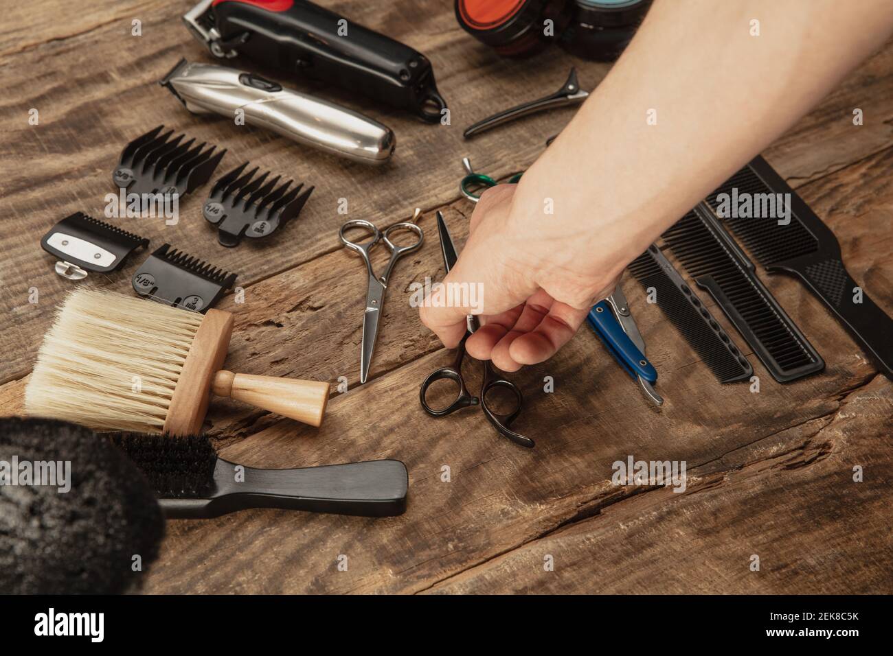 Hand of barber with equipment set on wooden table background. Close up ...
