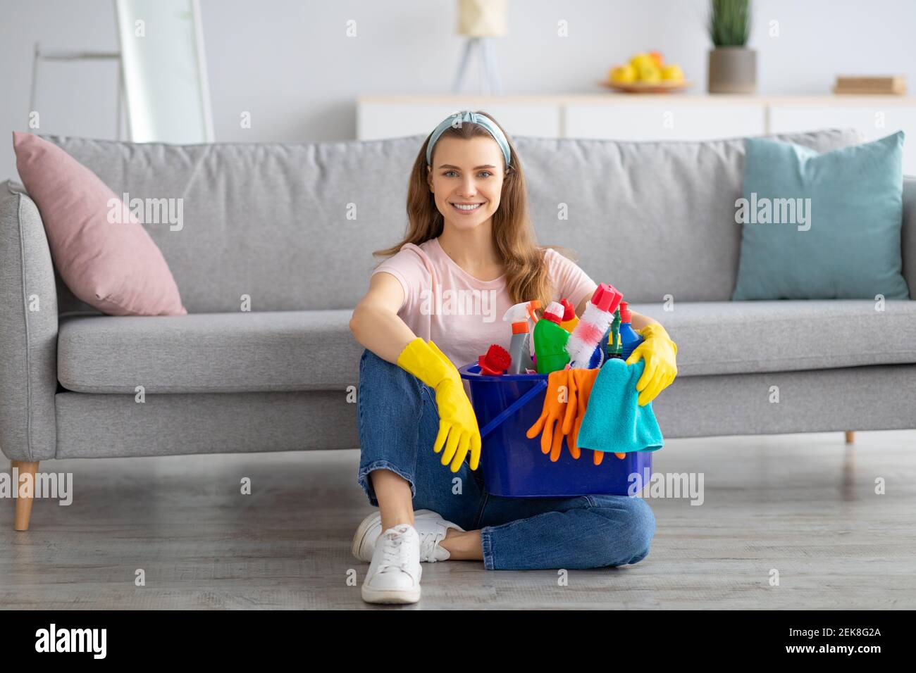 Full length portrait of happy young maid with bucket of cleaning ...