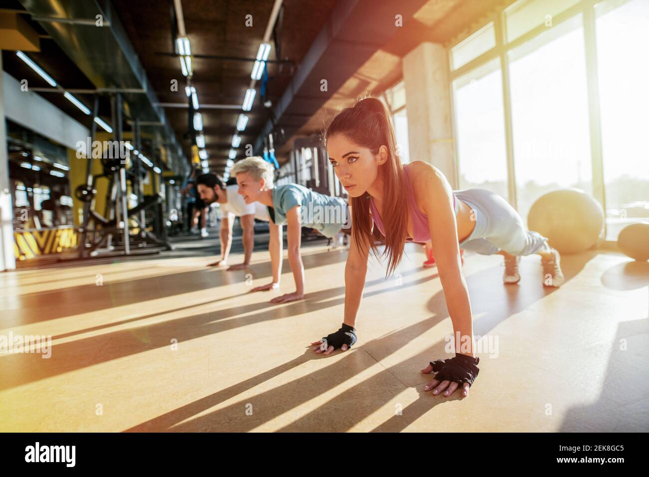 Tree strong people working out in a gym. Doing push ups in a line Stock ...