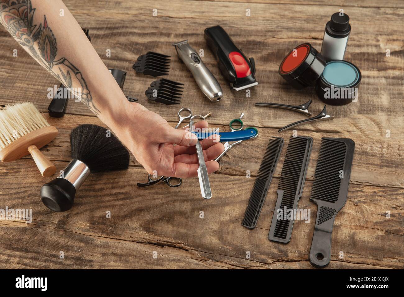 Hand of barber with equipment set on wooden table background. Close up ...