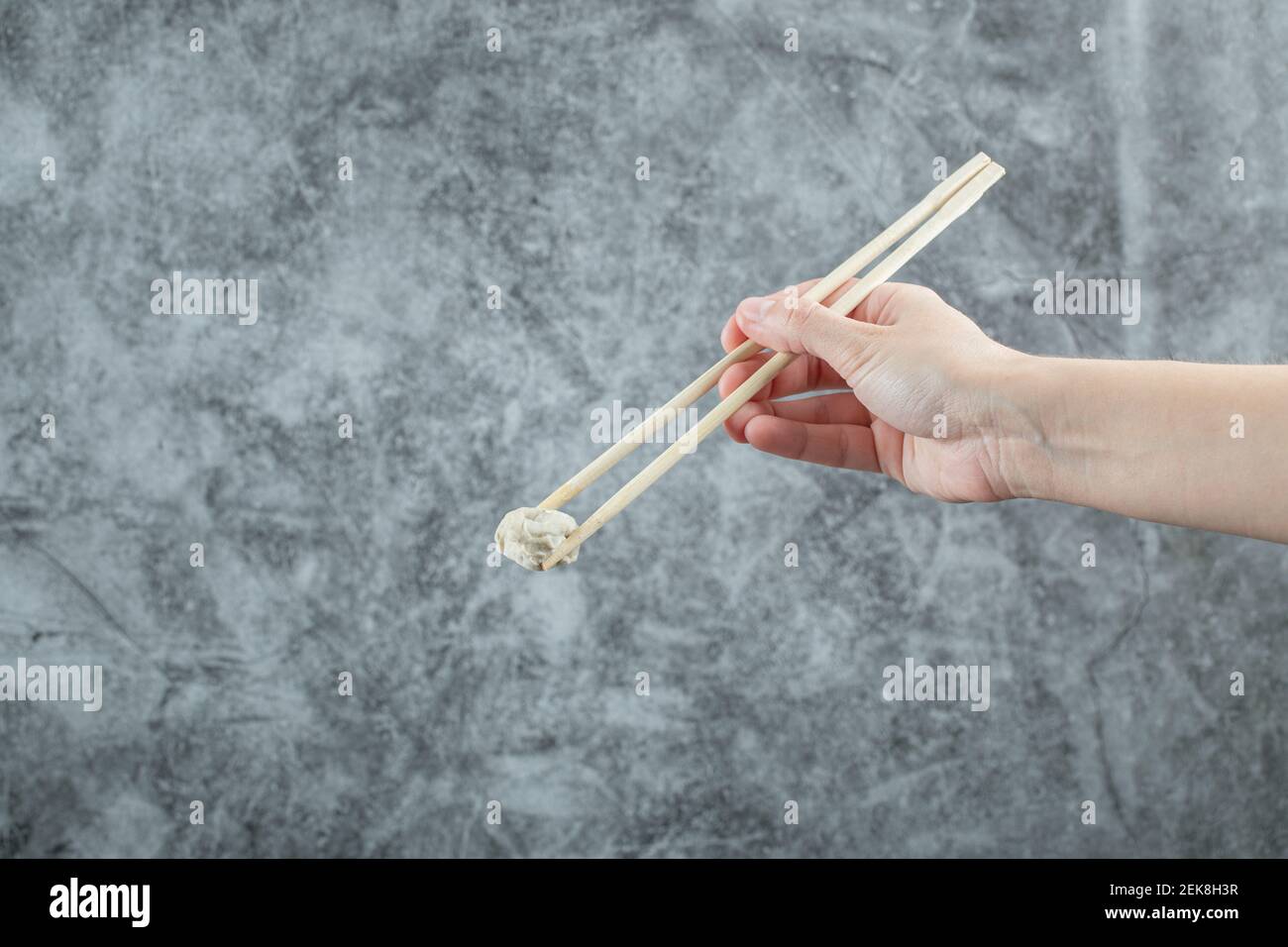 Hand holding a chopstick with a dumpling Stock Photo - Alamy