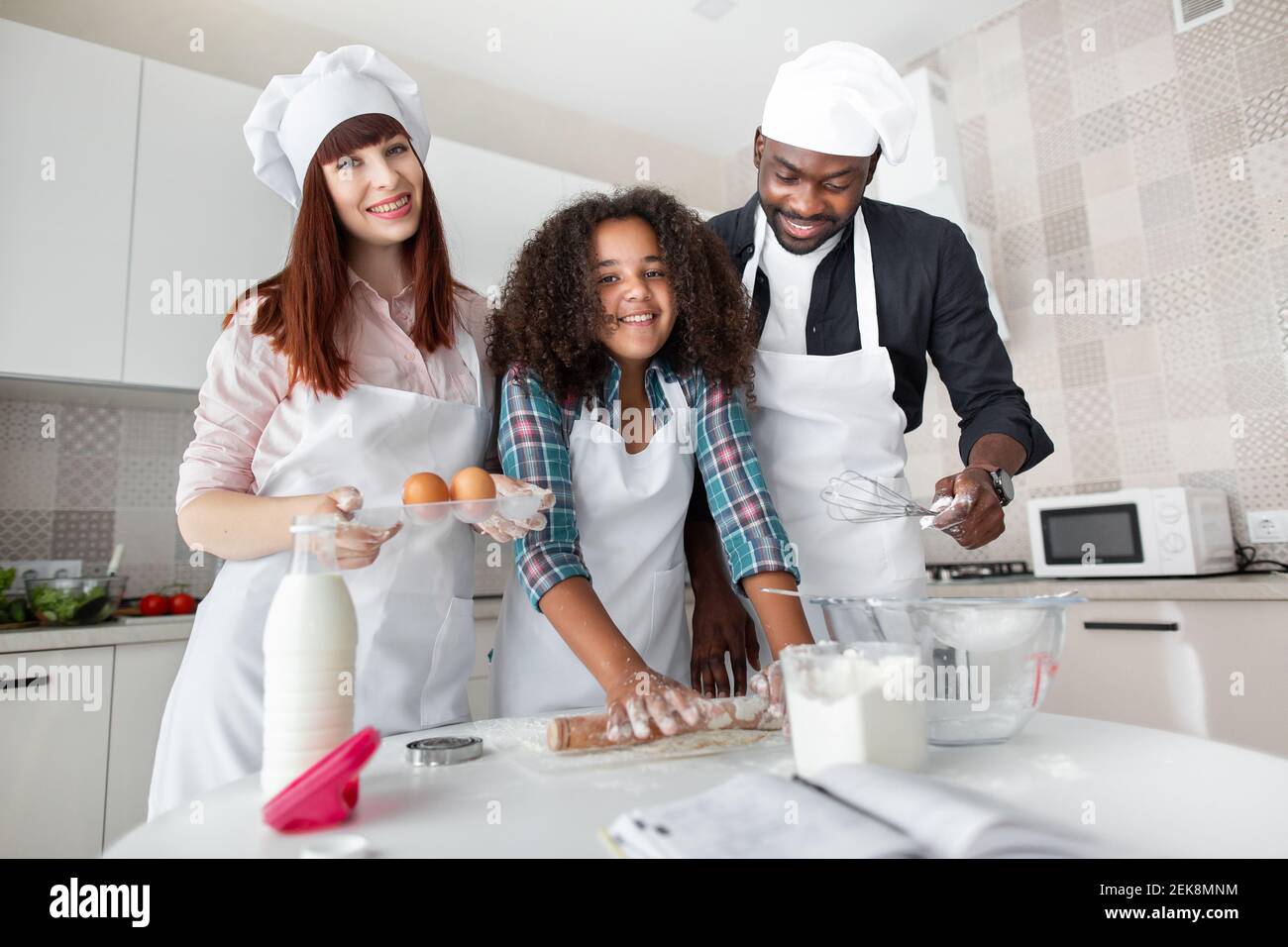 Parents teaching child doing bakery or pizza while cooking together in ...