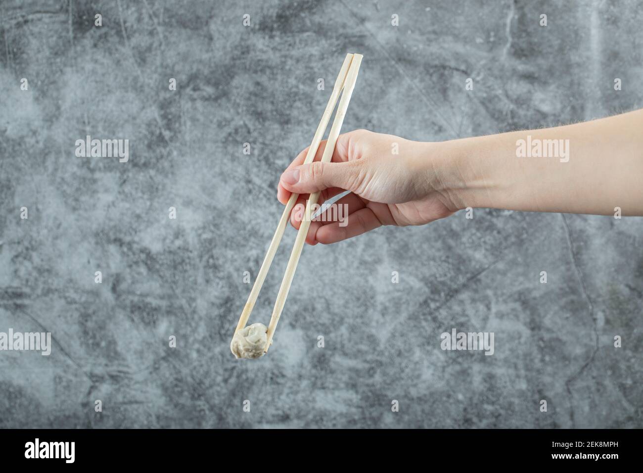 Hand holding a chopstick with a dumpling Stock Photo - Alamy