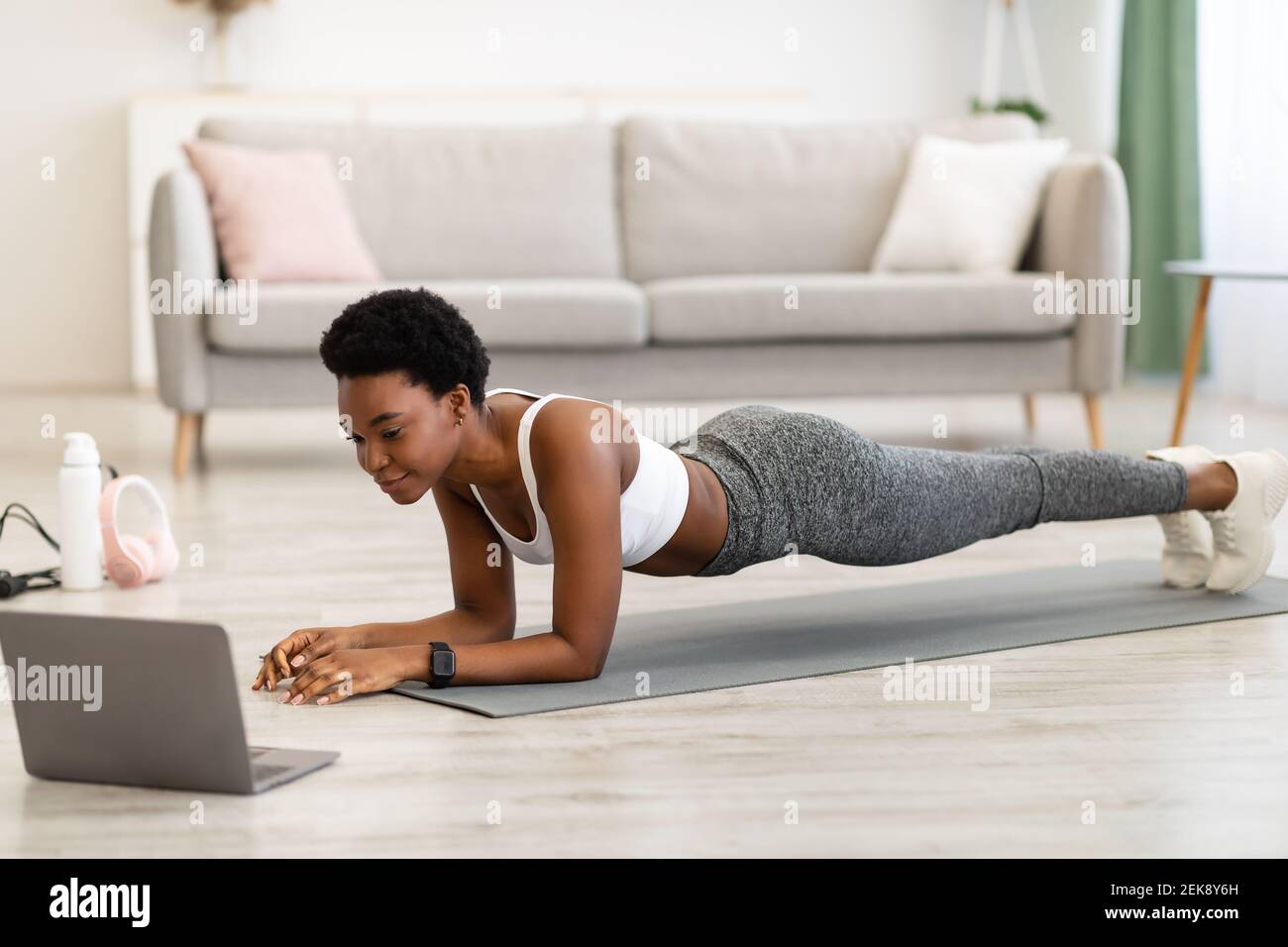 African Lady Standing In Plank Position Exercising At Laptop Indoor ...