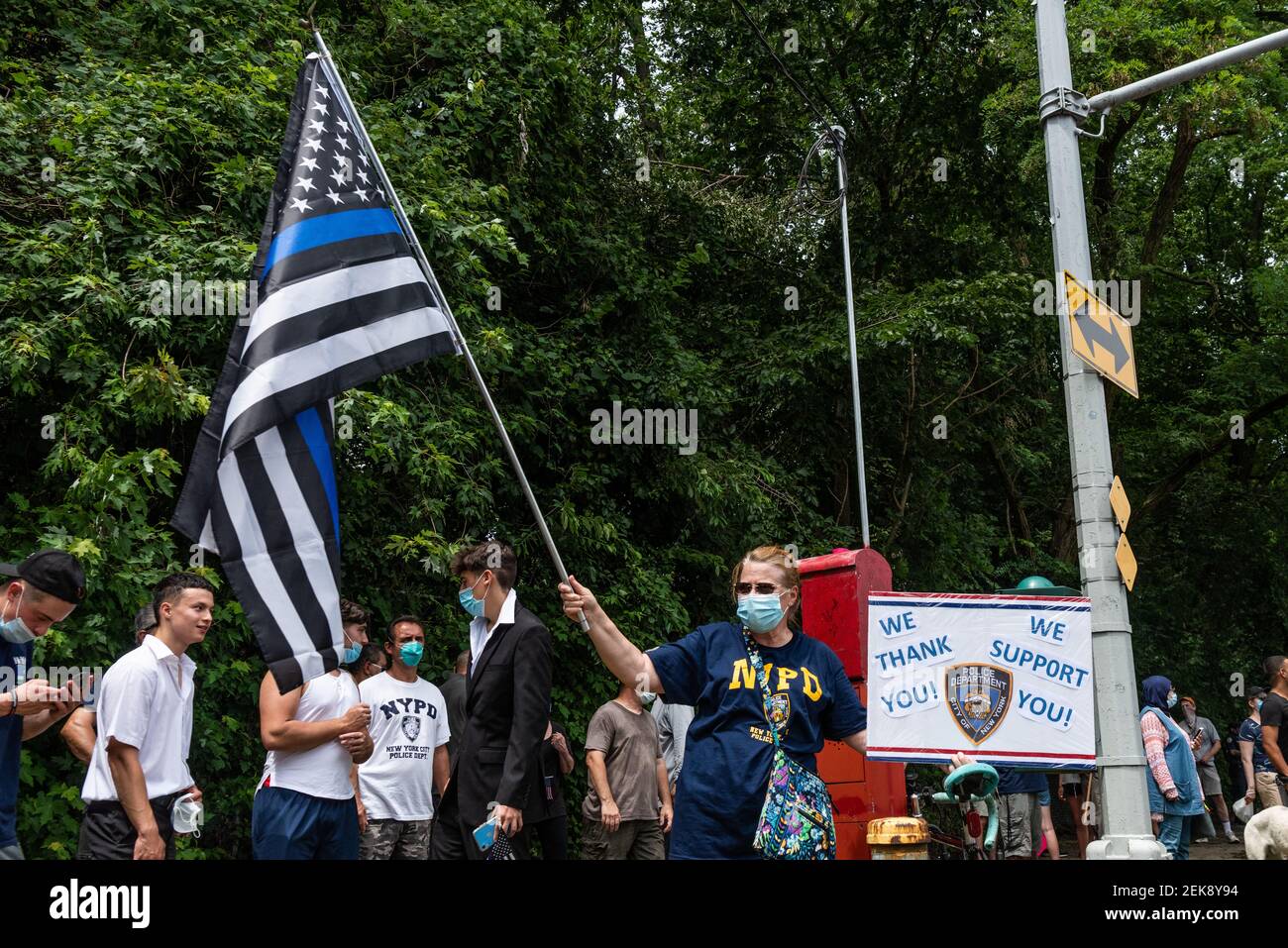 A woman holding a "Thin Blue Line" flag and a sign thanking the NYPD ...