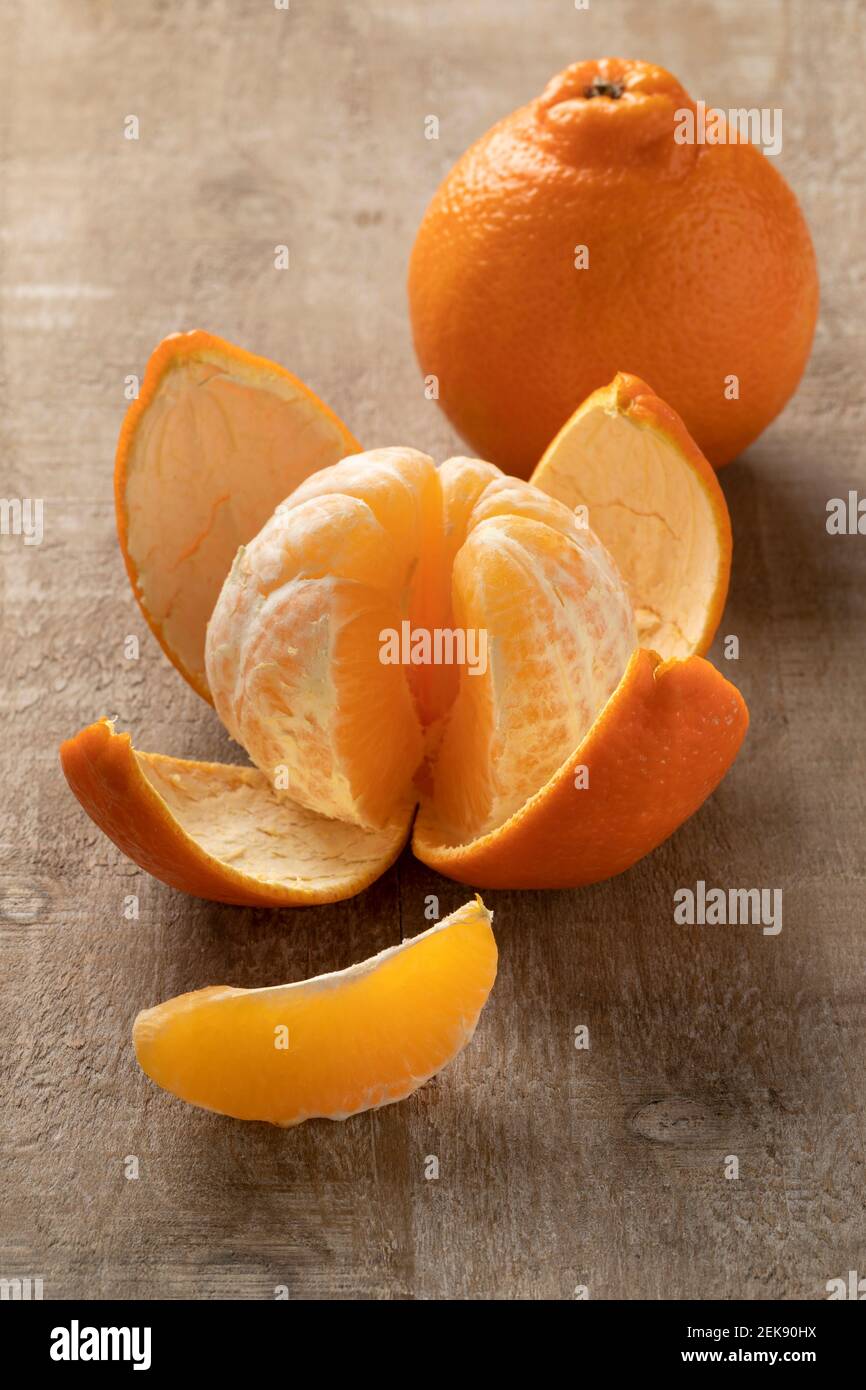 Fresh group of Minneola tangelos and a peeled one in front close up ...