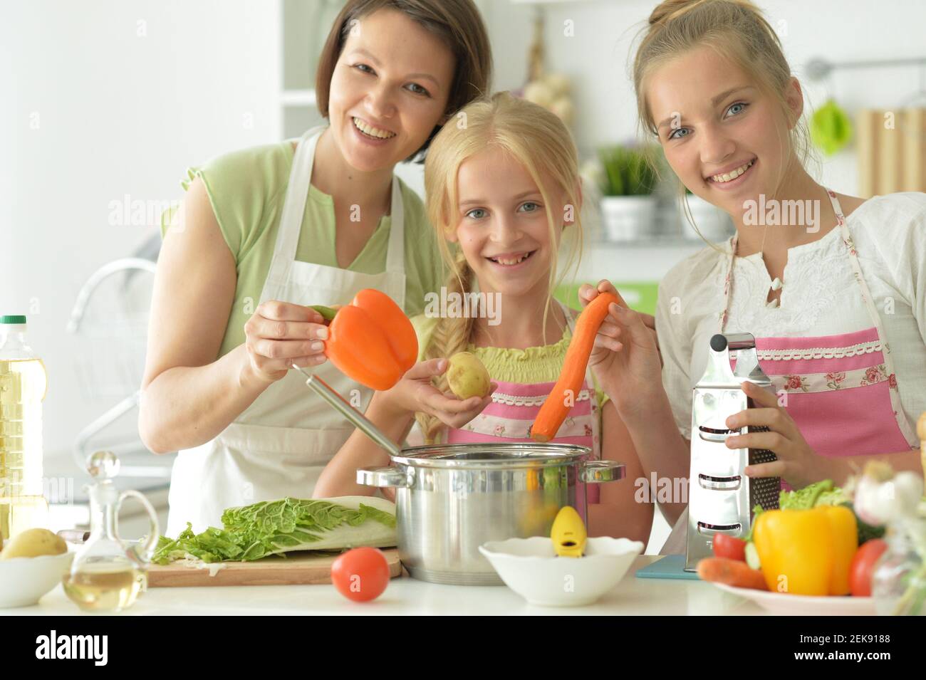 Cute girls with mother cooking in kitchen Stock Photo - Alamy