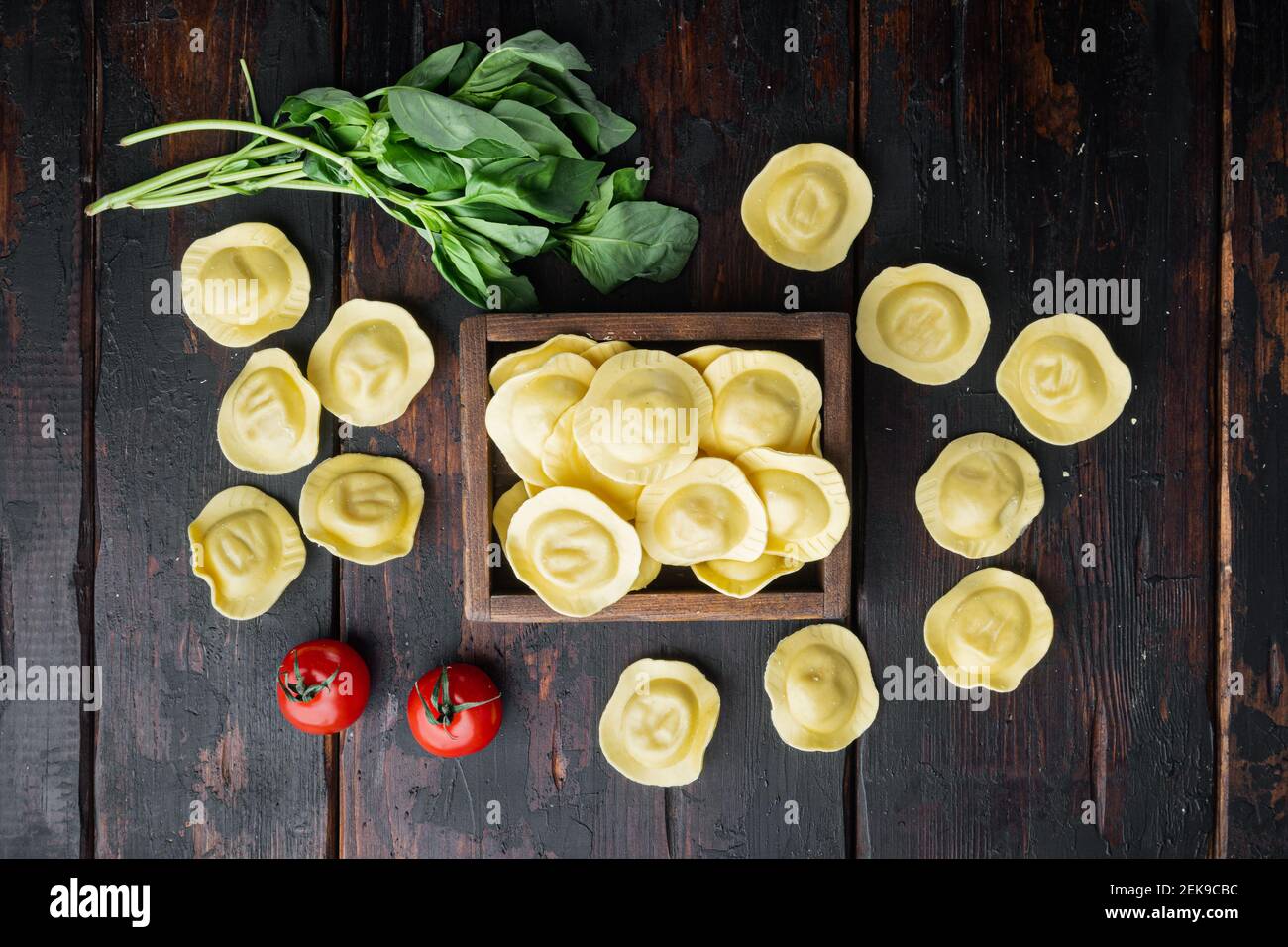 Raw Ravioli with basil and tomatoes set, in wooden box, on old dark ...