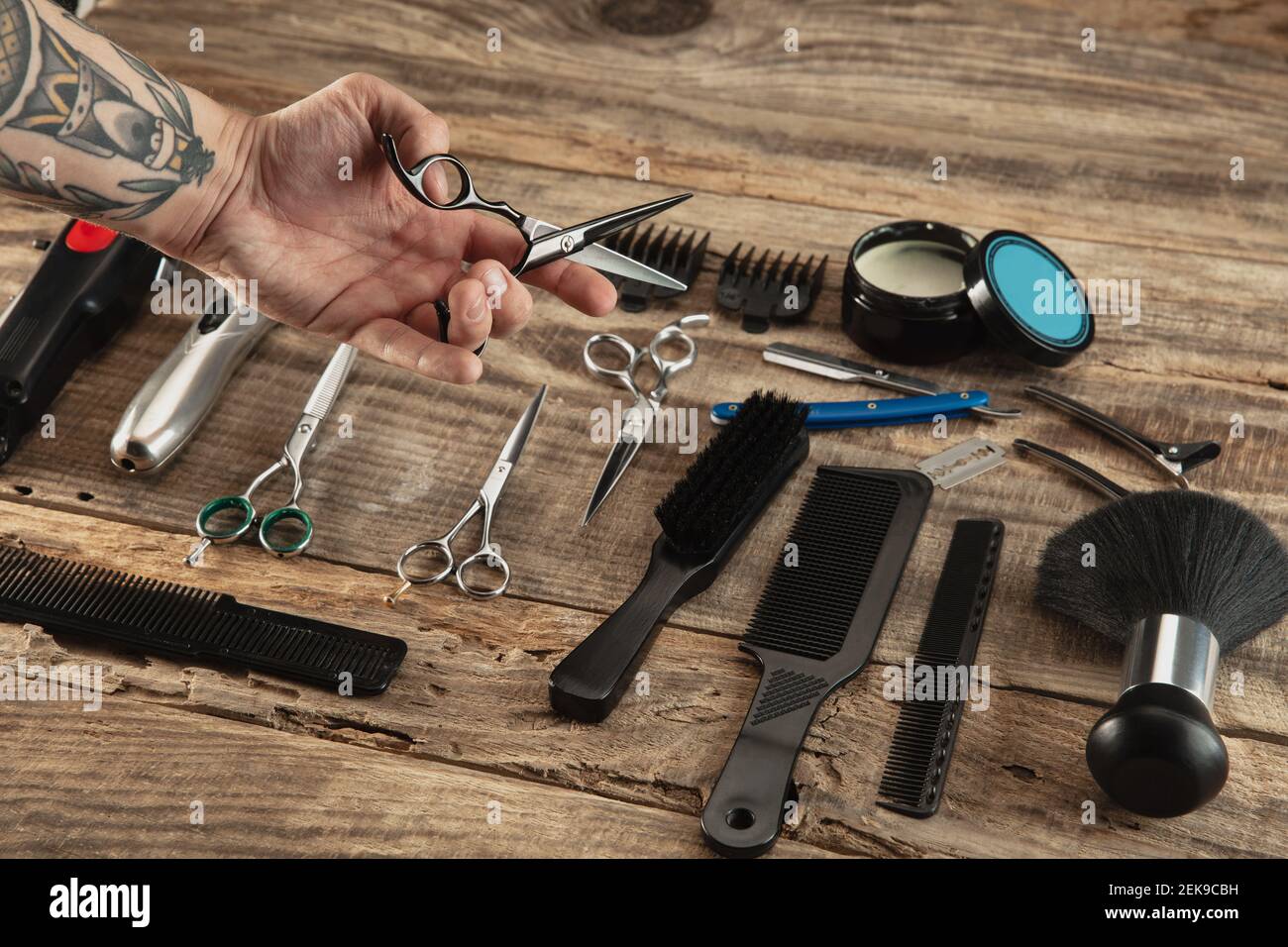 Hand of barber with equipment set on wooden table background. Close up ...