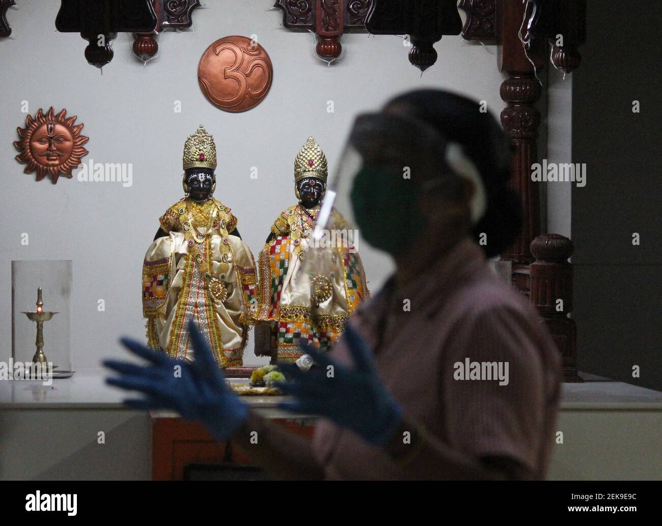 Healthcare worker stands near an idol of Hindu God Vitthal and his ...
