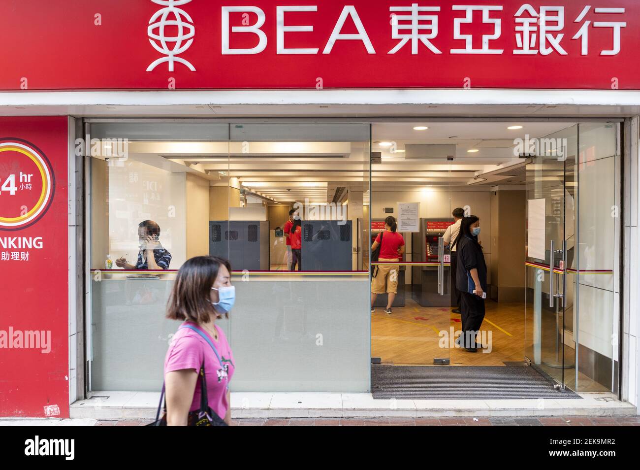 A pedestrian wearing a face mask walks past Bank of East Asia (BEA) branch and logo seen in Hong ...