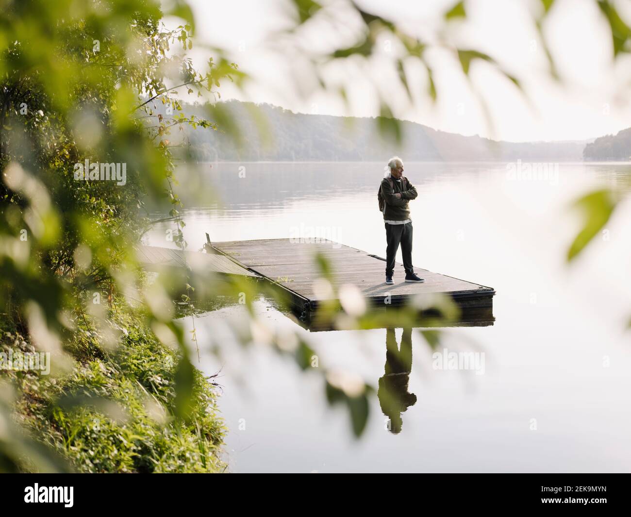 Explorer looking at view while standing with arms crossed on pier Stock ...