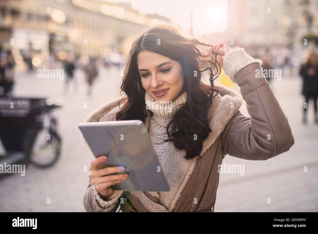 Beautiful woman using tablet and standing on street in cold weather ...