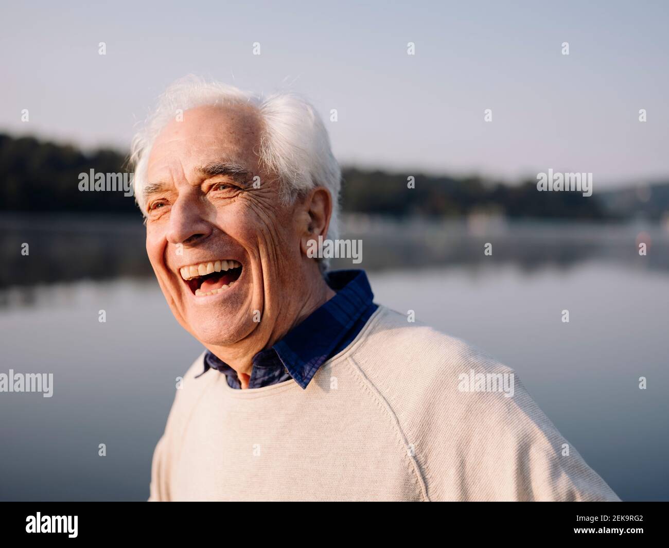 Man laughing while standing against lake Stock Photo - Alamy