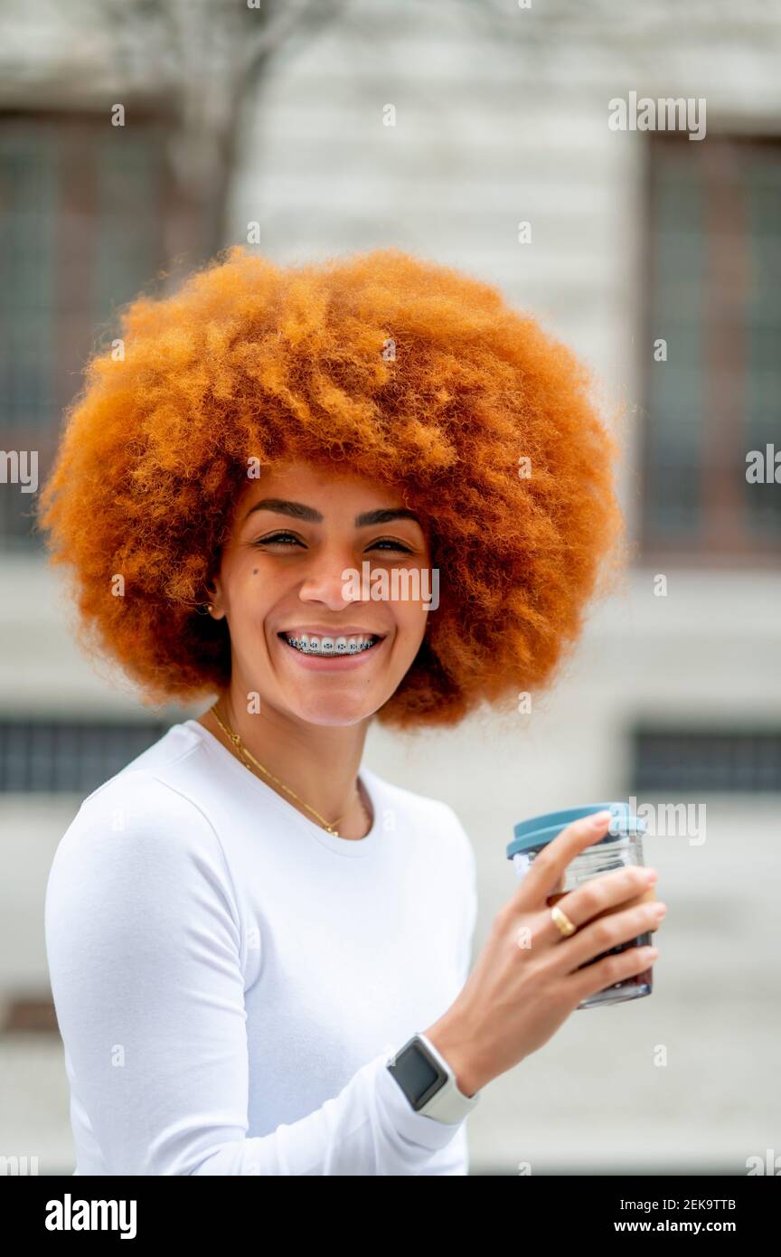 Smiling woman drinking coffee while standing outdoors Stock Photo - Alamy
